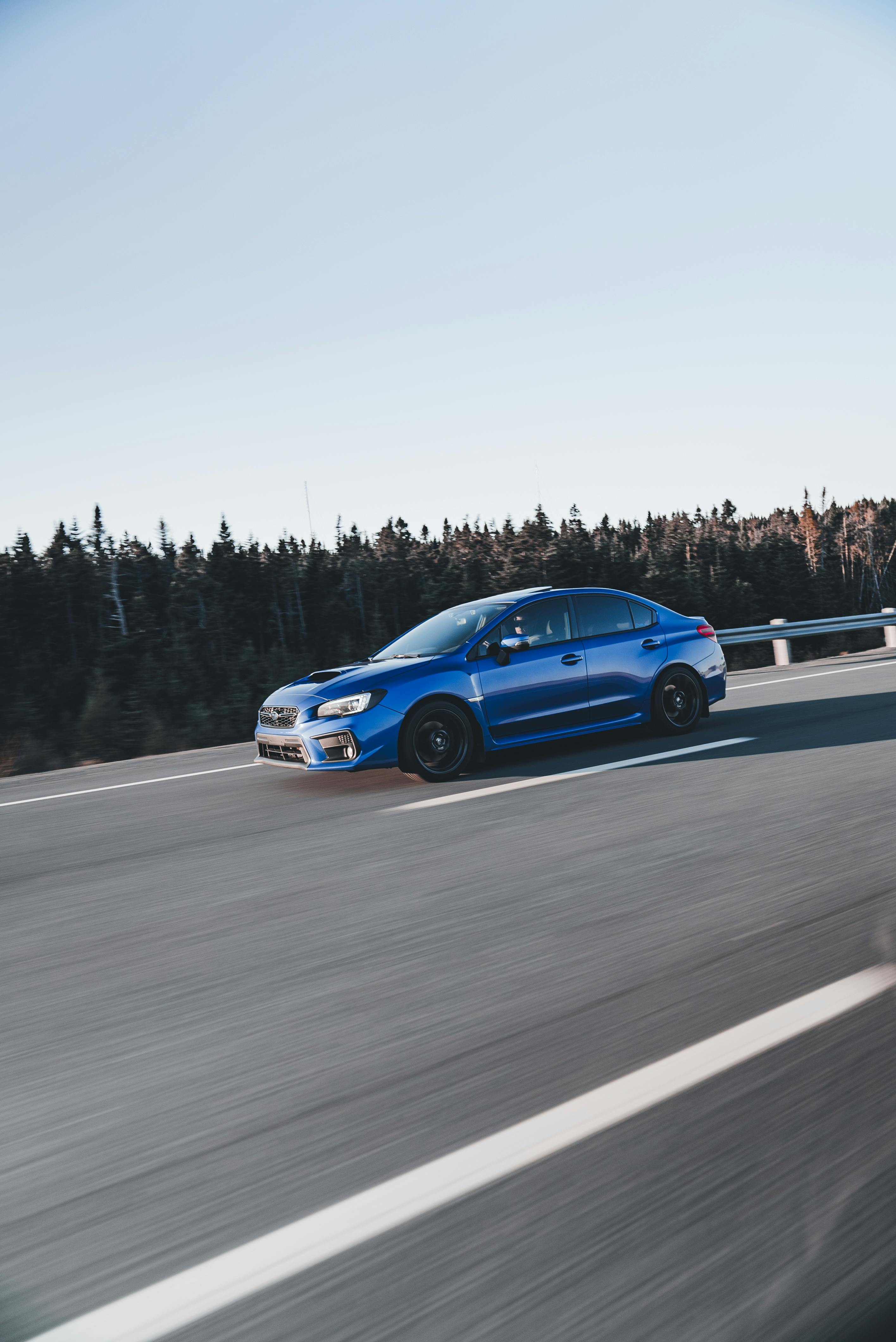 Blue sports car speeding on a highway · Free Stock Photo