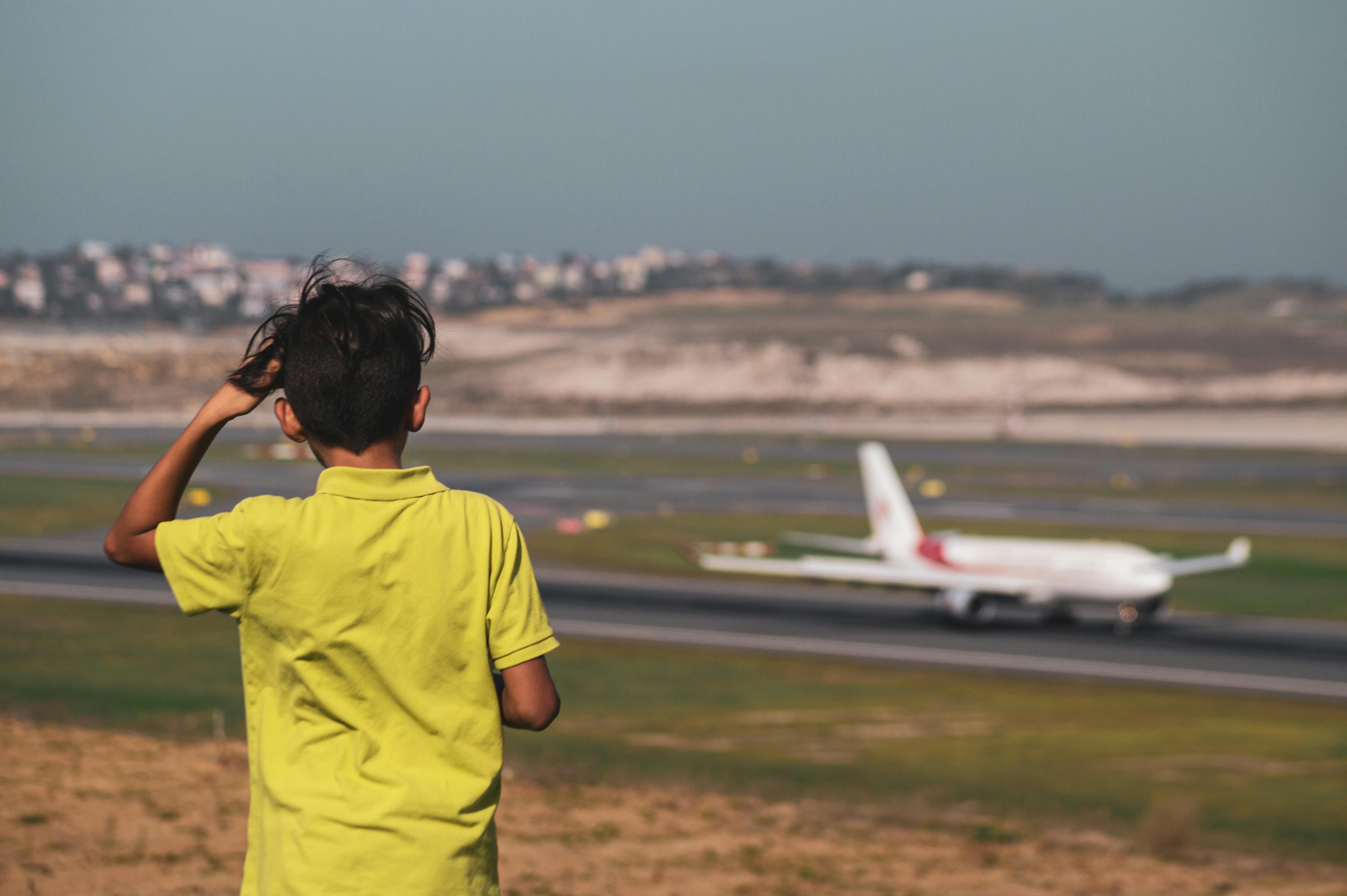 Child Watching Airplane Takeoff at Airport · Free Stock Photo