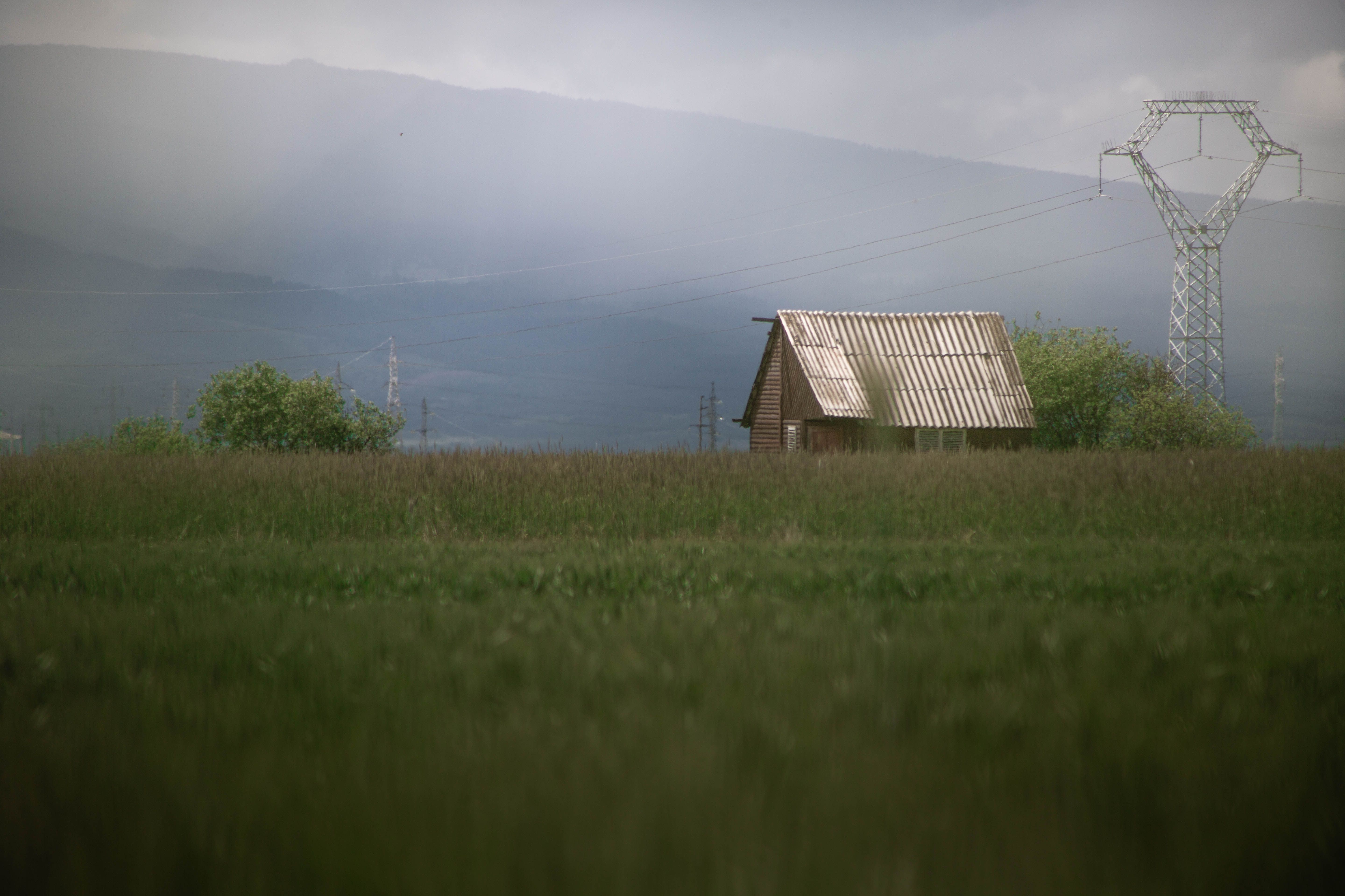 Rustic Cabin in Vast Field Under Overcast Sky · Free Stock Photo