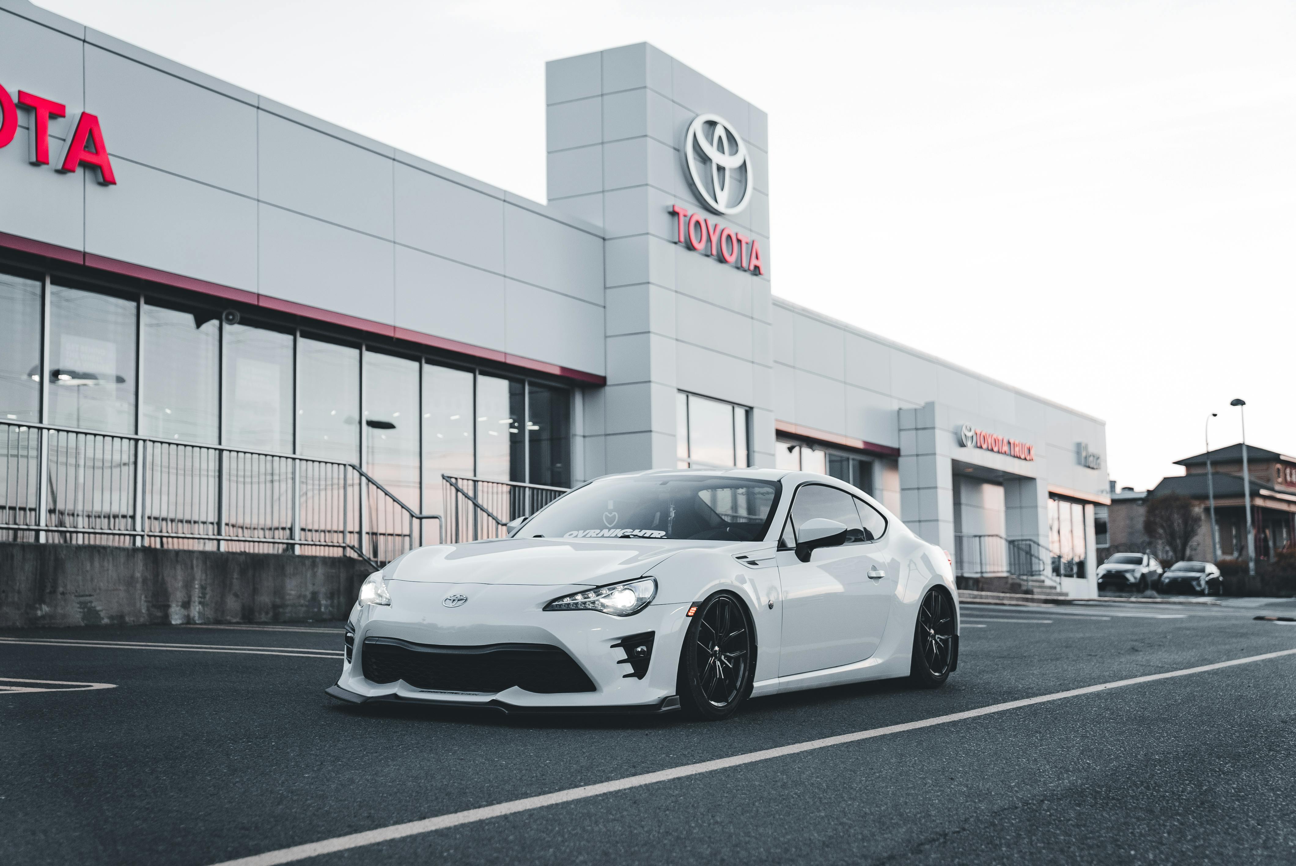 Sleek White Toyota Sports Car in Front of Dealership · Free Stock Photo