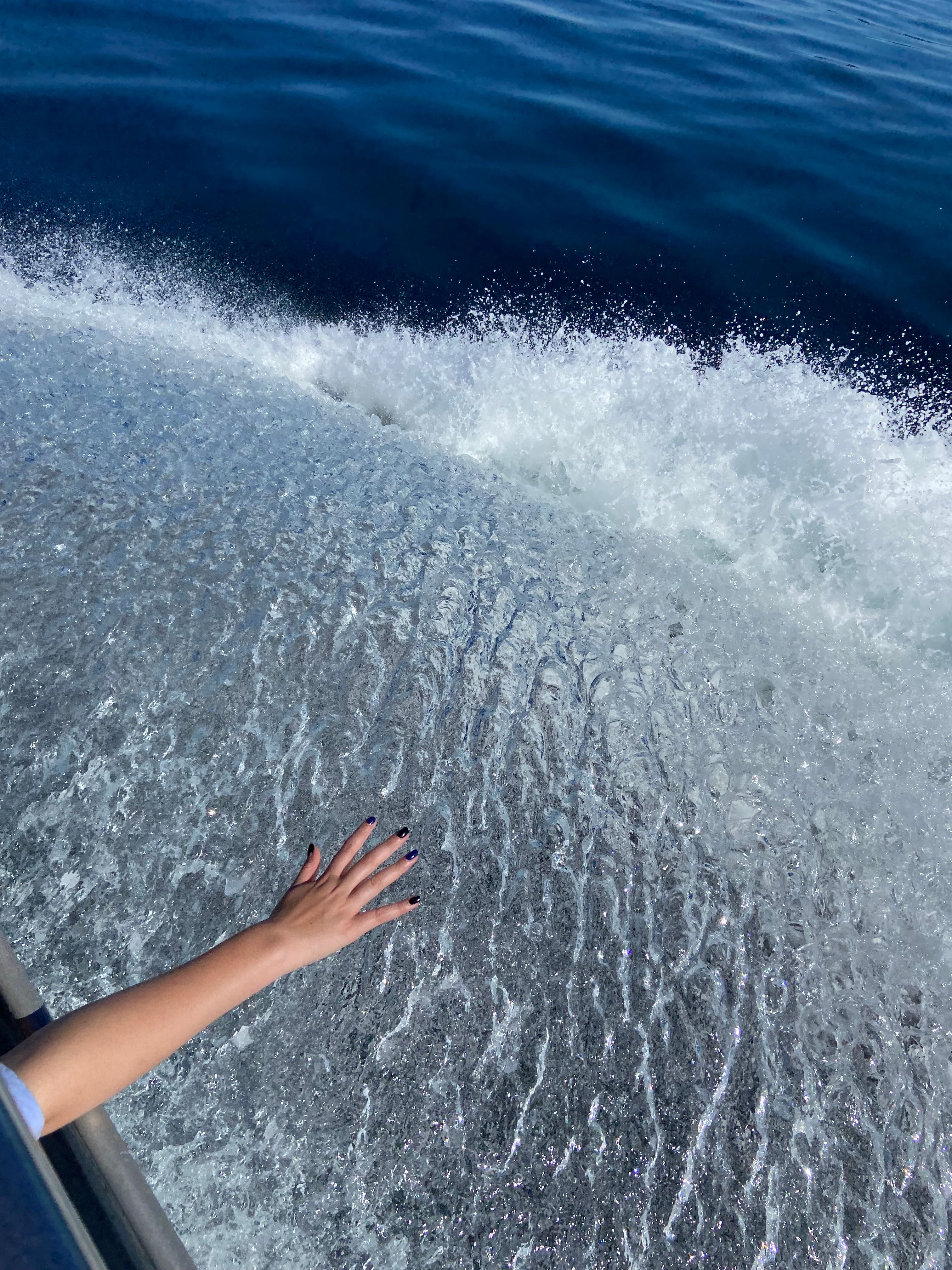 Serenity at Sea: Hand Touching Ocean Waves · Free Stock Photo