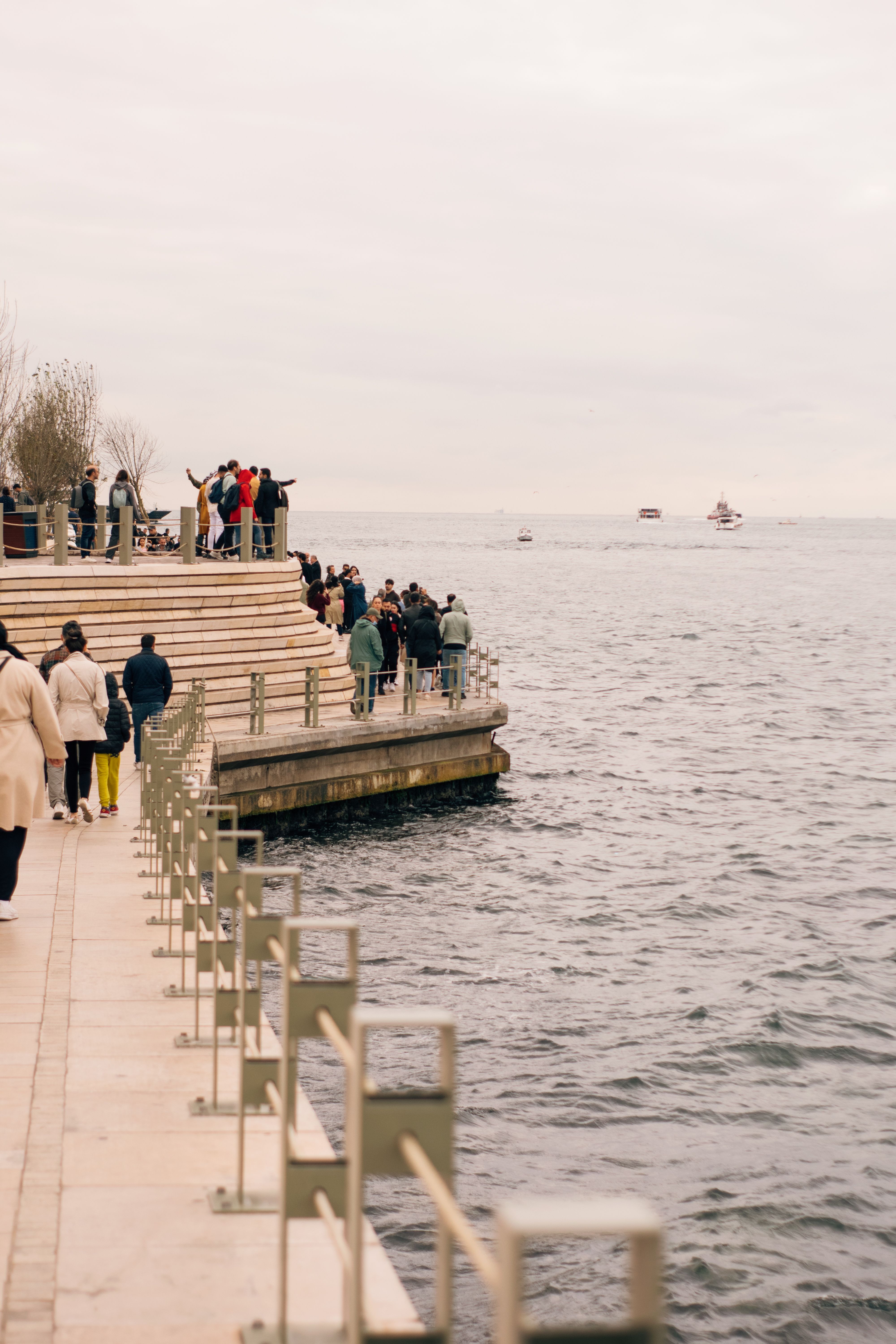 People enjoying a riverside promenade on a cloudy day · Free Stock Photo