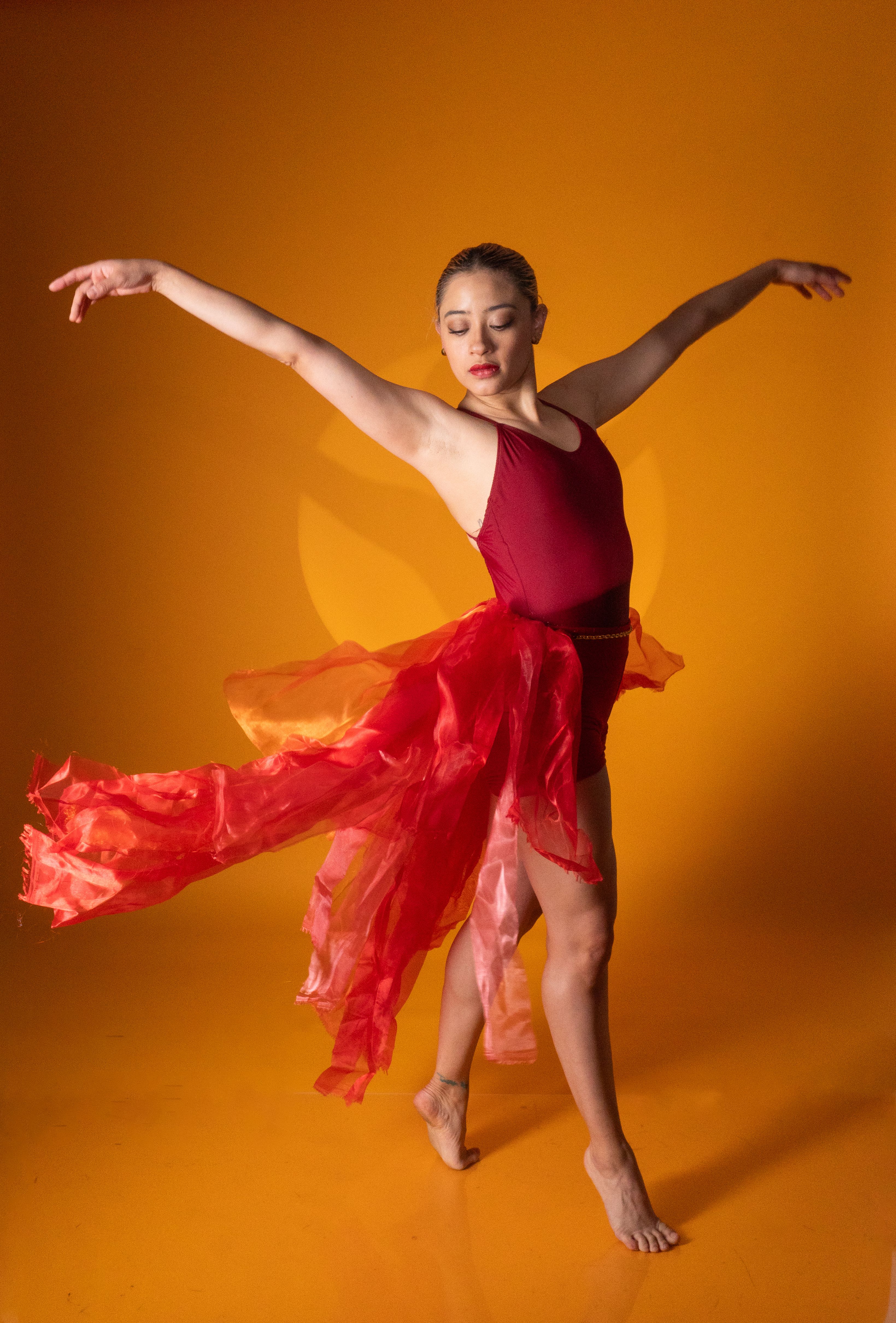 Expressive Female Dancer in Red on Orange Background · Free Stock Photo