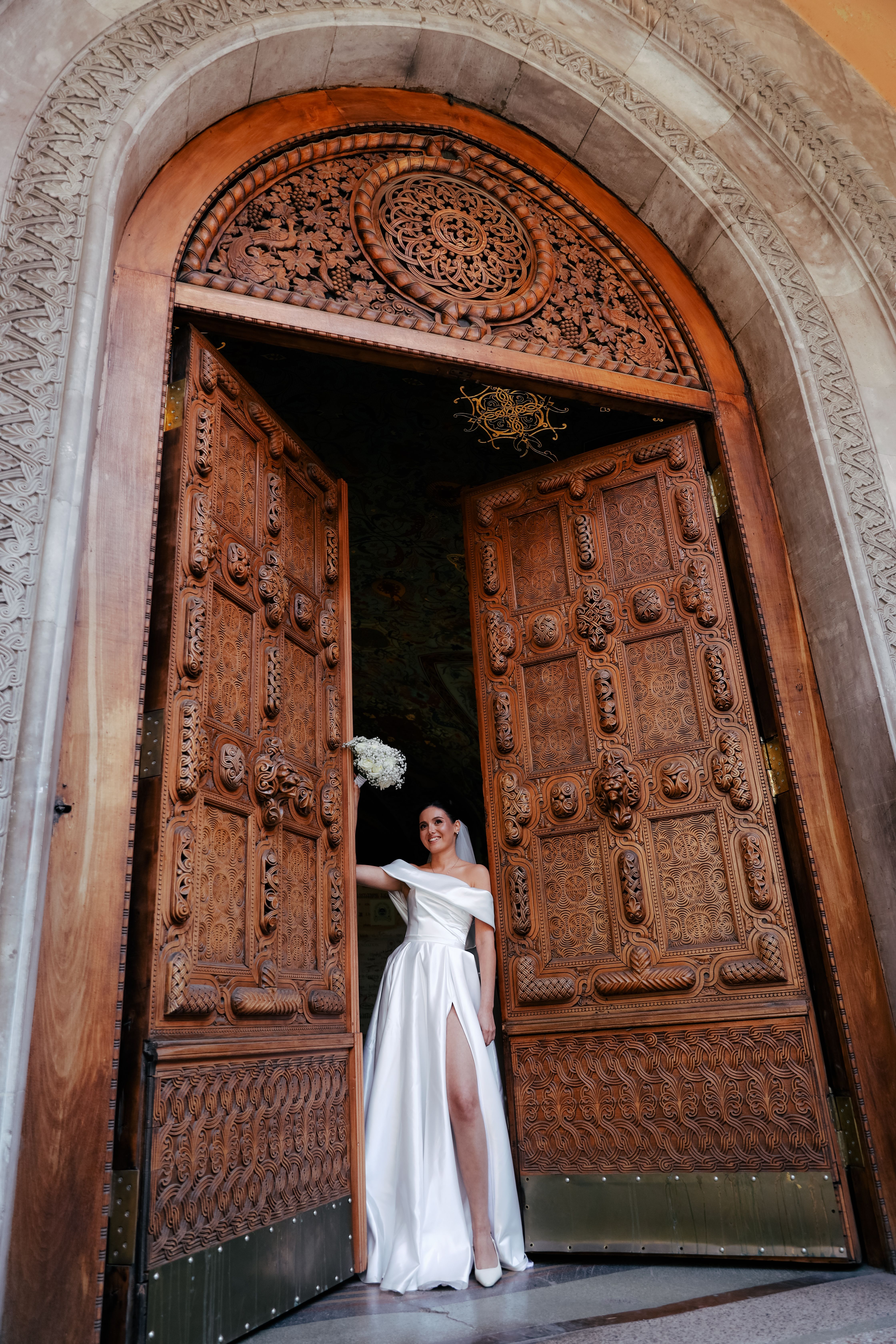 Elegant Bride at Ornate Wooden Church Doors · Free Stock Photo