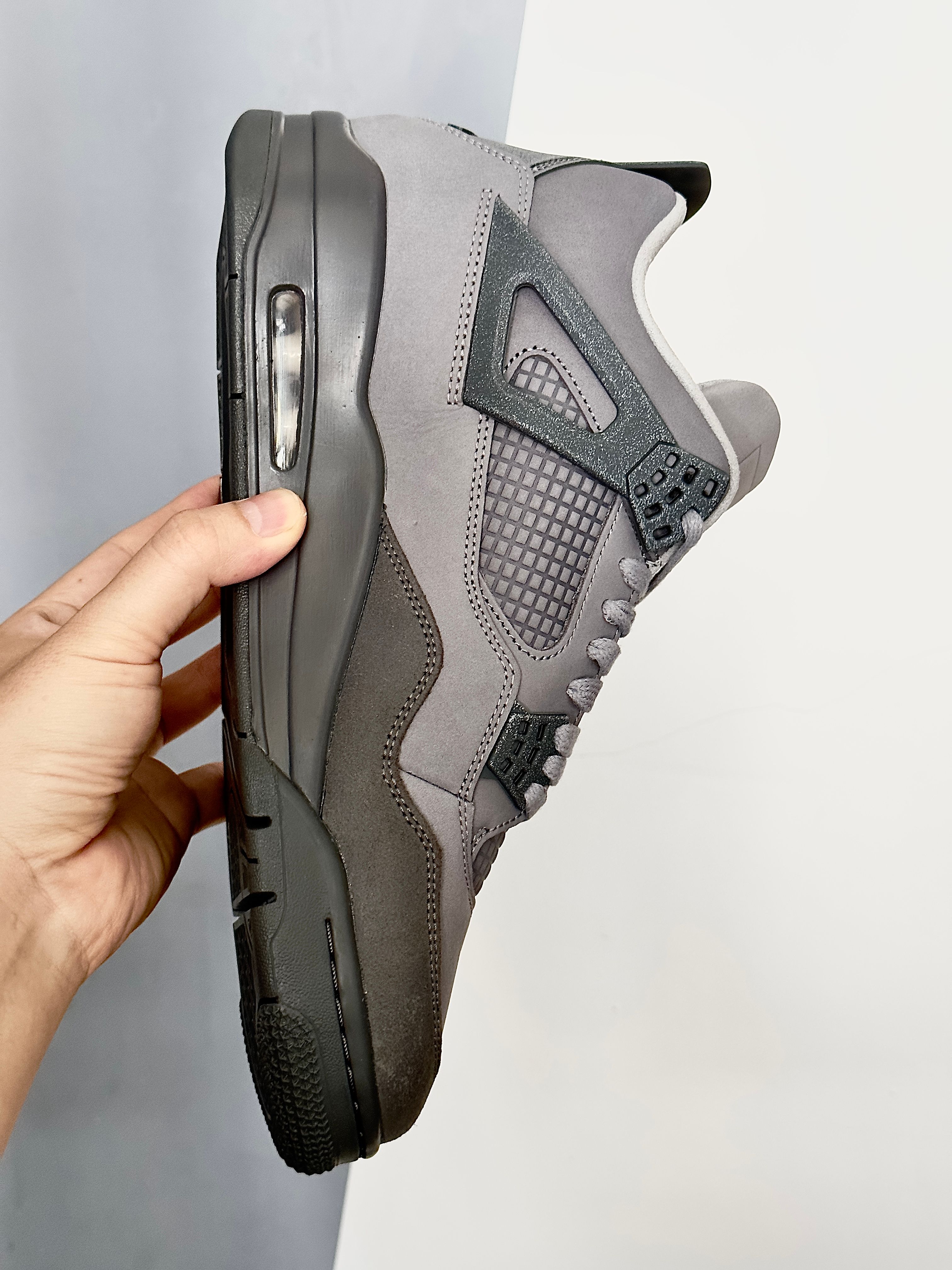 Gray Sneaker Held Against Neutral Background · Free Stock Photo
