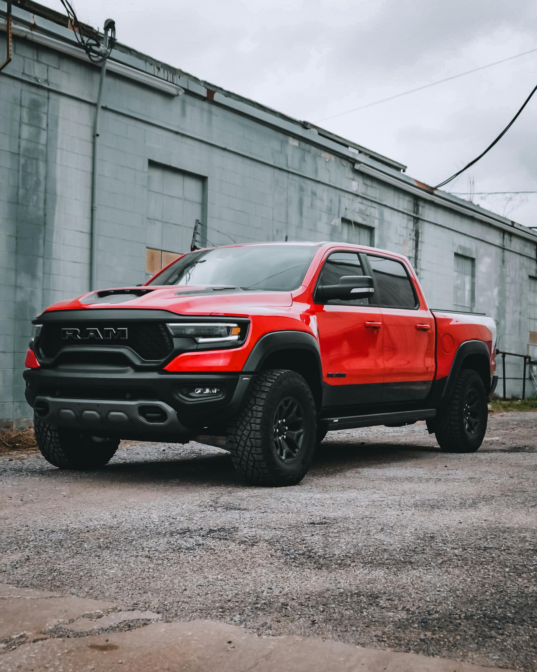 Red RAM Truck with Black Rims in Industrial Setting · Free Stock Photo