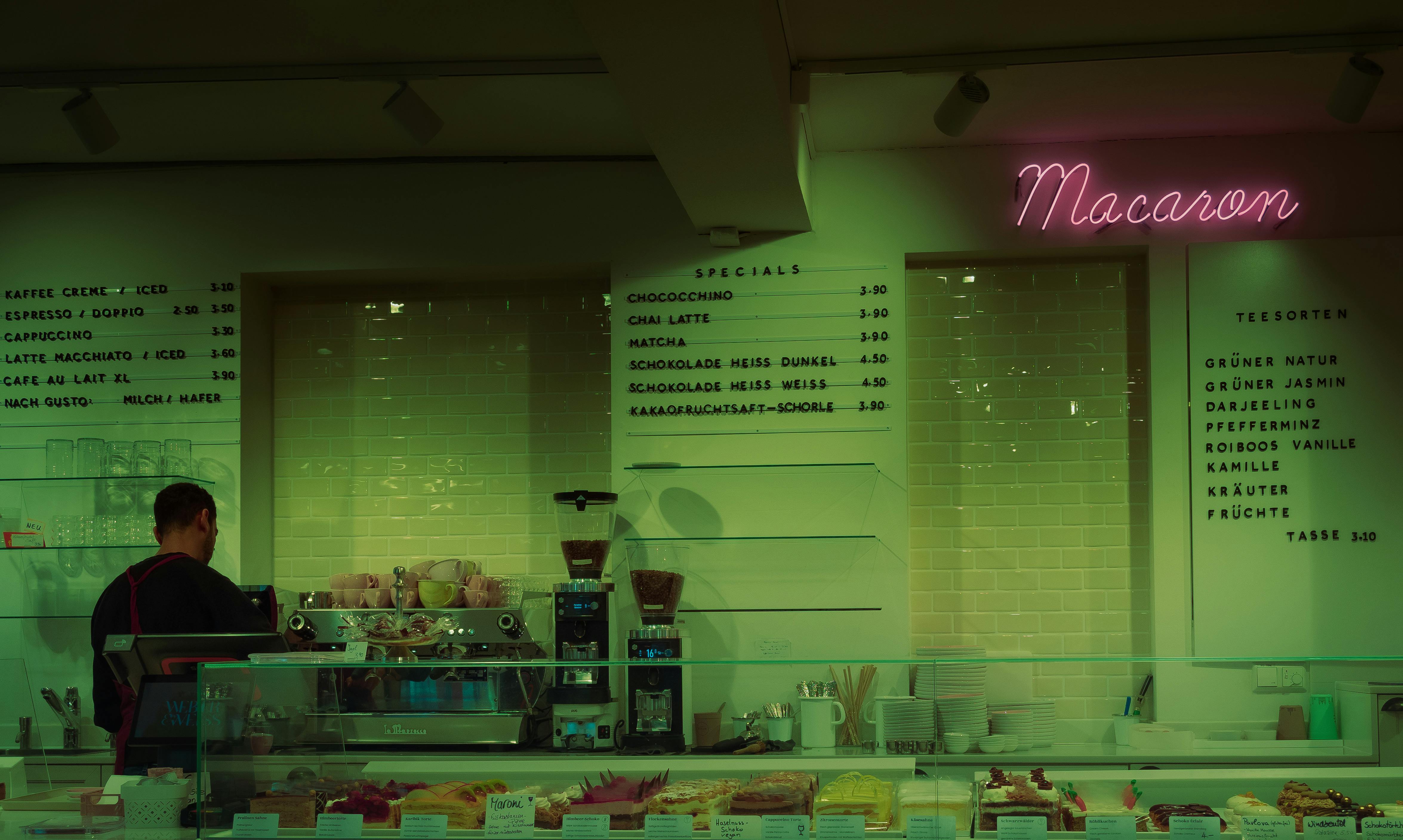 Cozy Cafe Interior with Neon Macaron Sign · Free Stock Photo