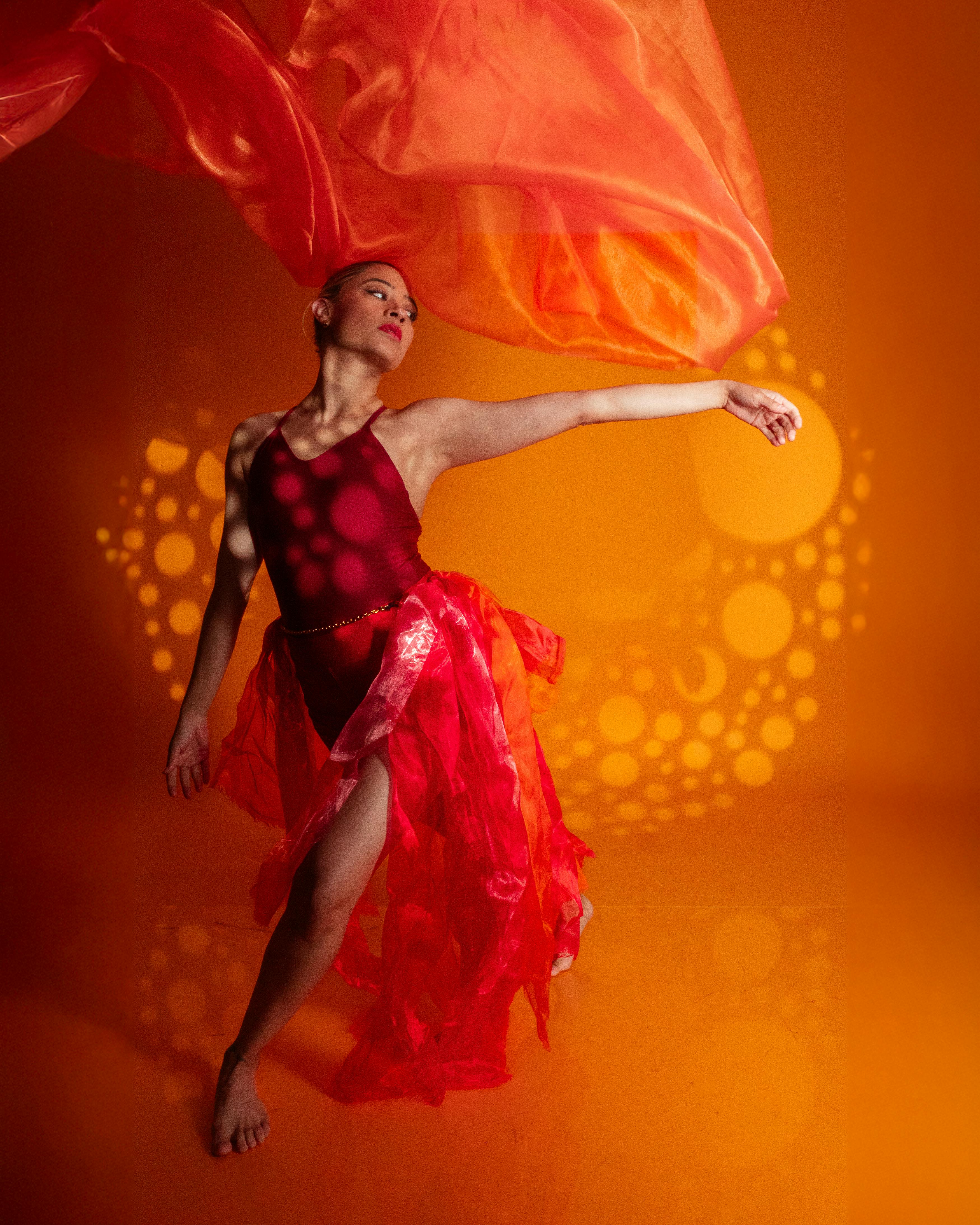 Dynamic Ballet Dancer Against Vibrant Orange Backdrop · Free Stock Photo
