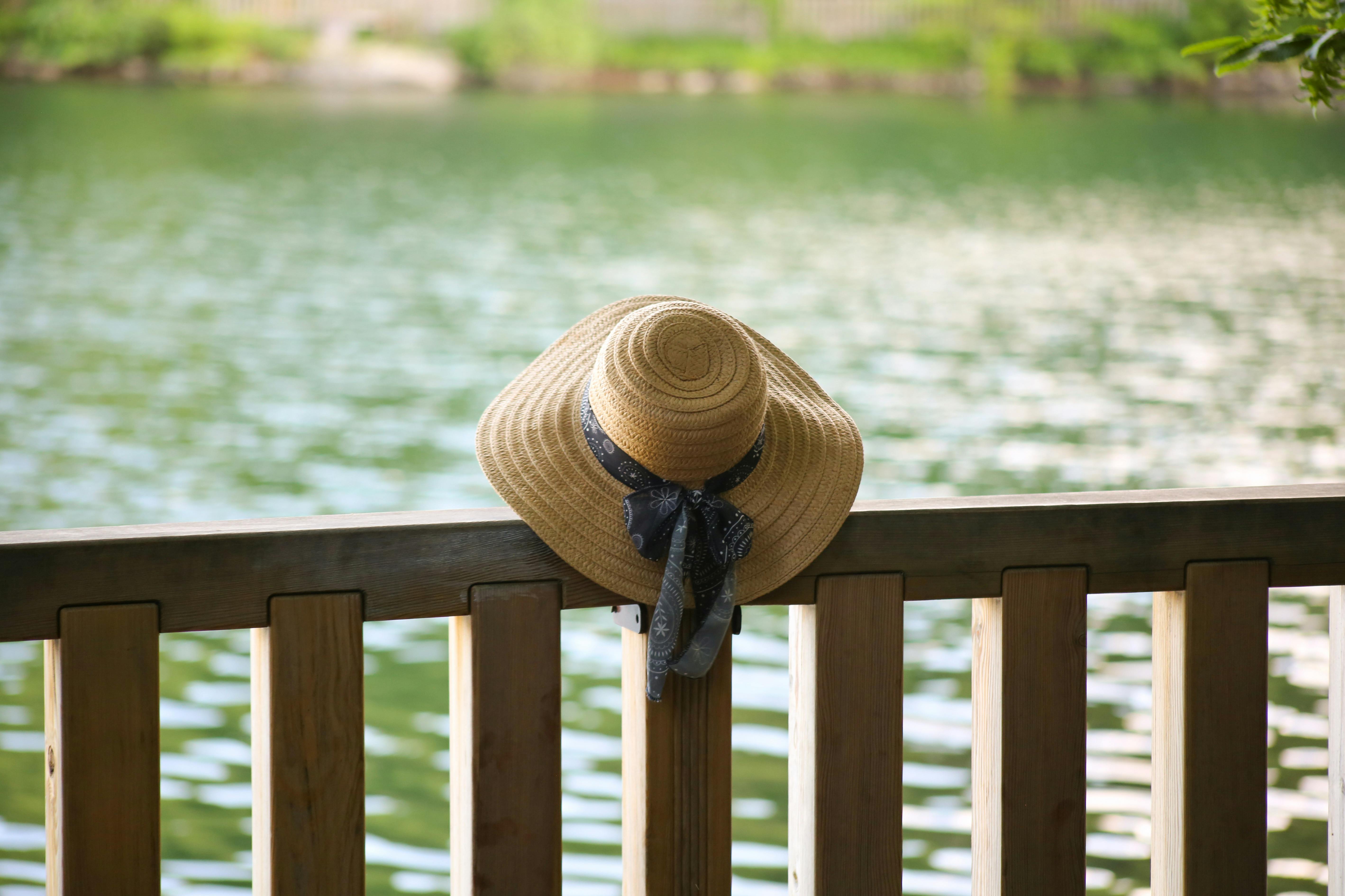 Straw Hat on Railing by a Serene Lake · Free Stock Photo