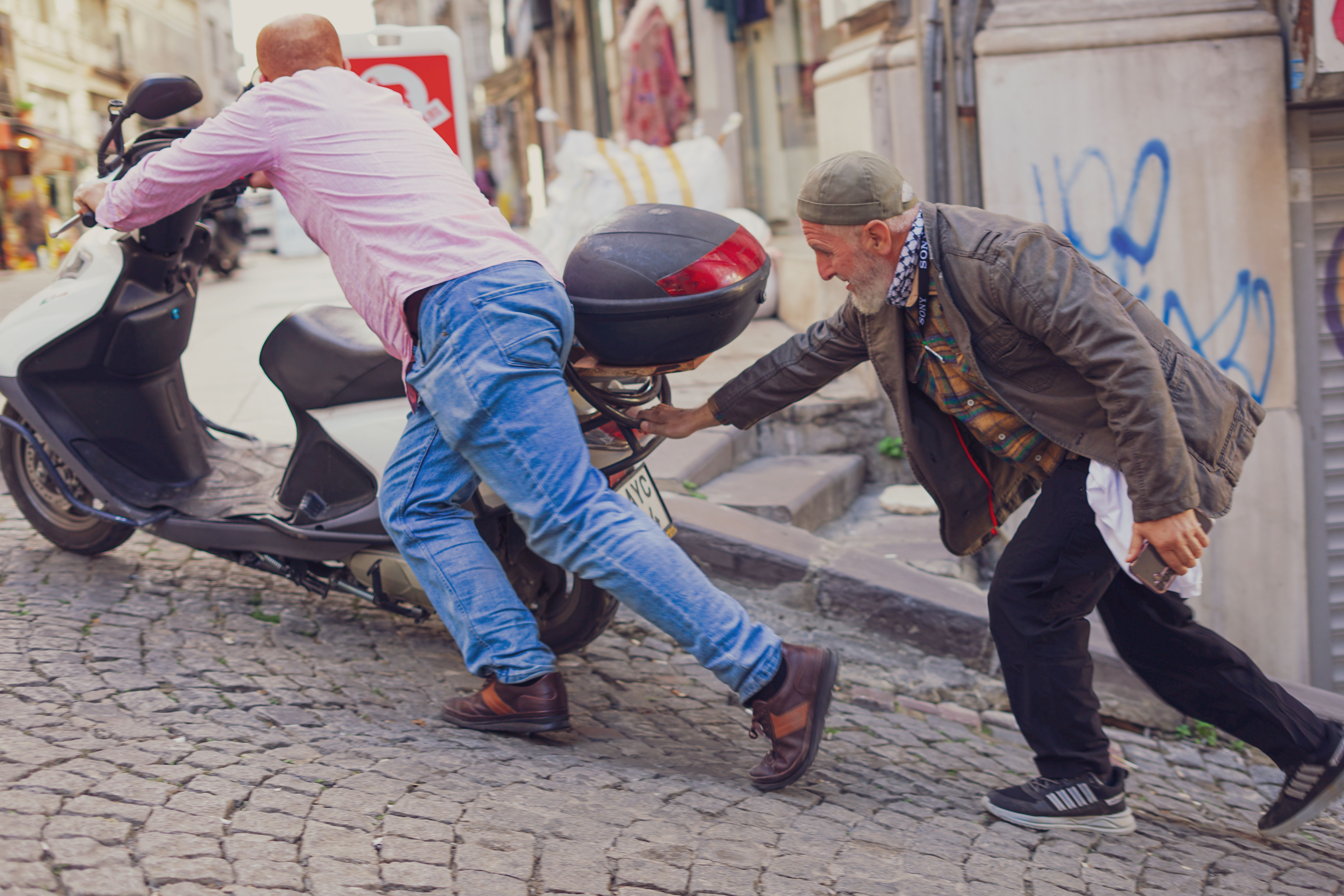 Two Men Pushing Scooter on Cobblestone Street in İstanbul · Free Stock ...