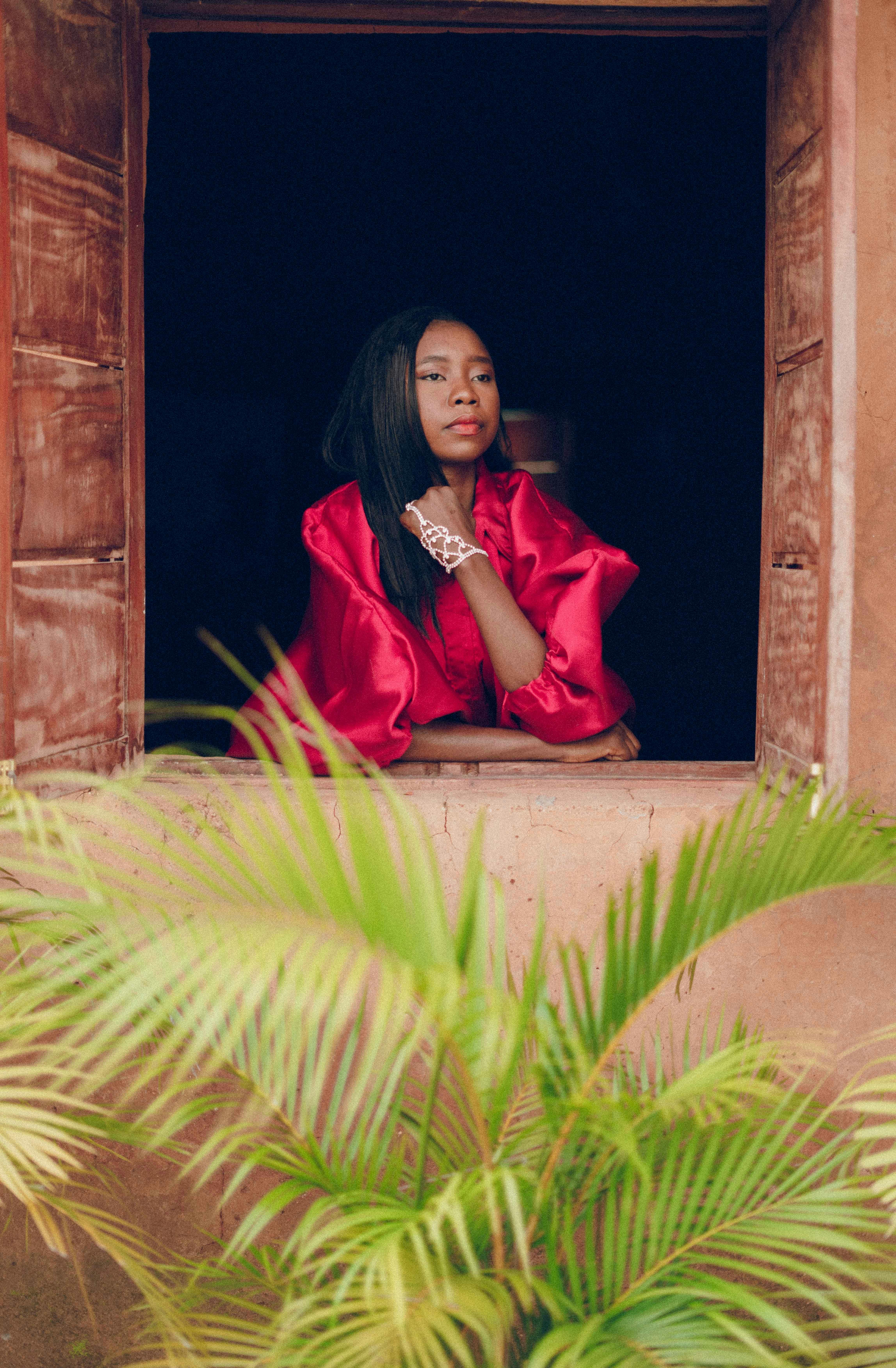 Elegant Woman in Red Outfit by Nigerian Window · Free Stock Photo