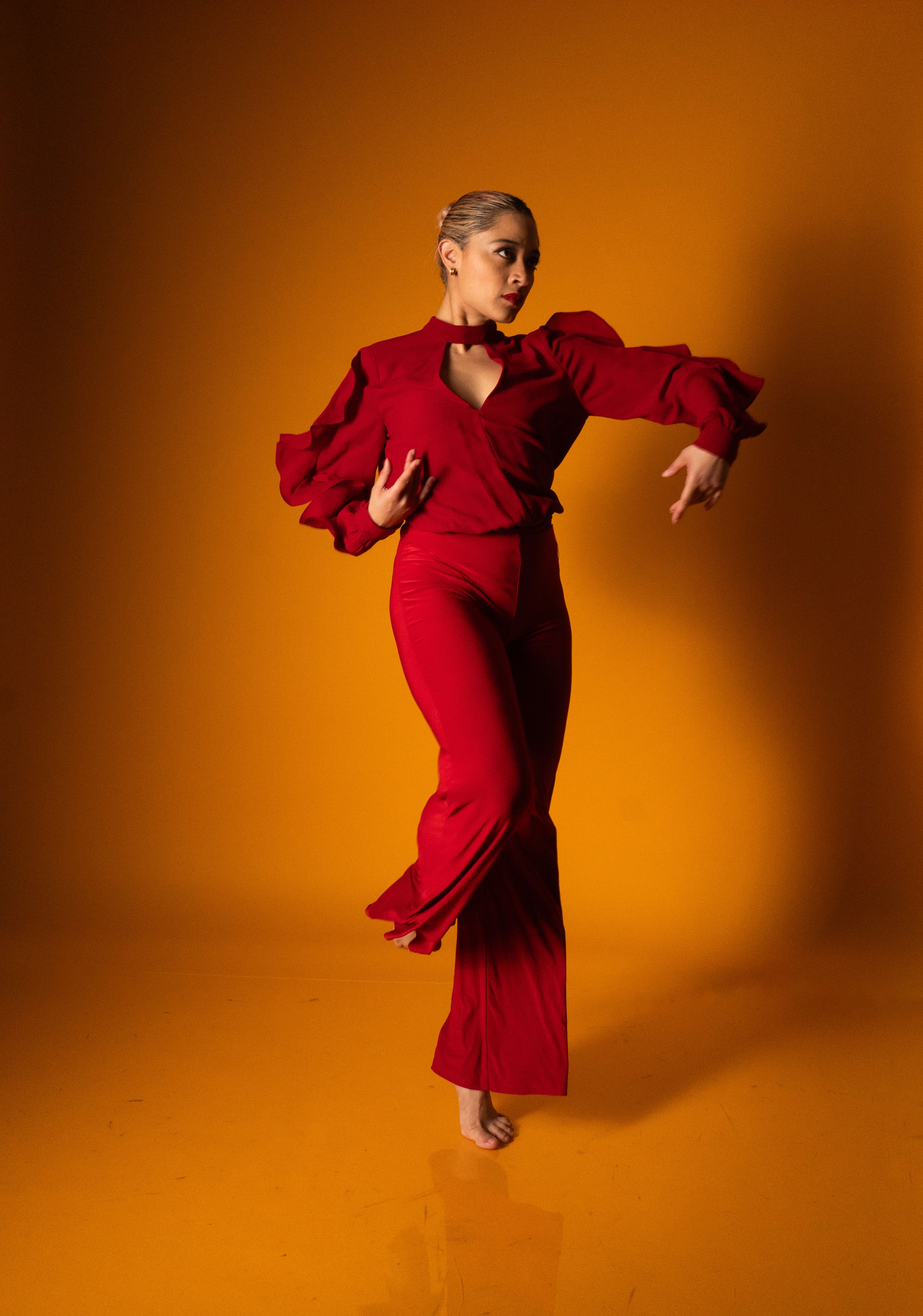 Graceful Dancer in Red Against Vibrant Orange Backdrop · Free Stock Photo