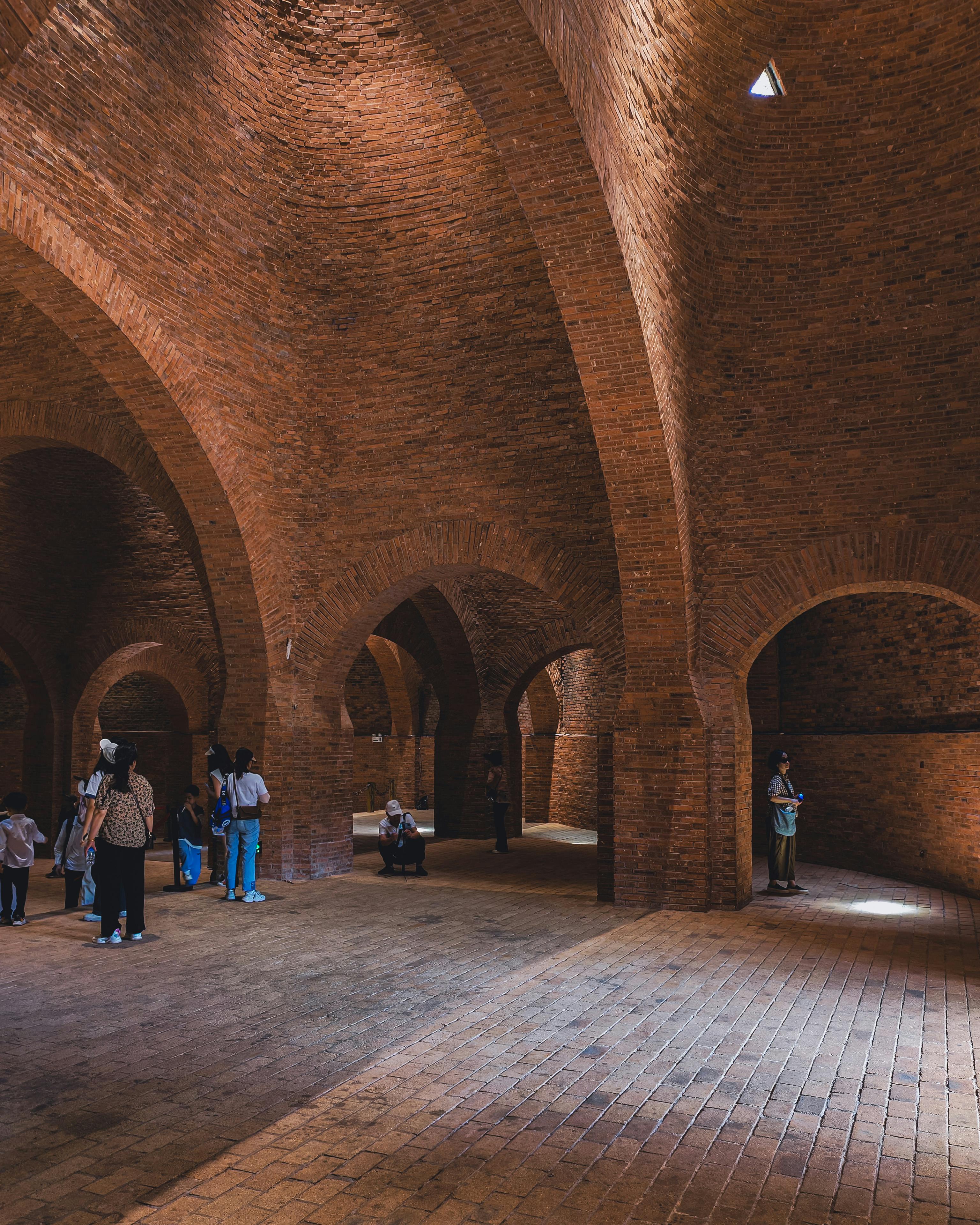Tourists Exploring Ancient Brick Vaults · Free Stock Photo