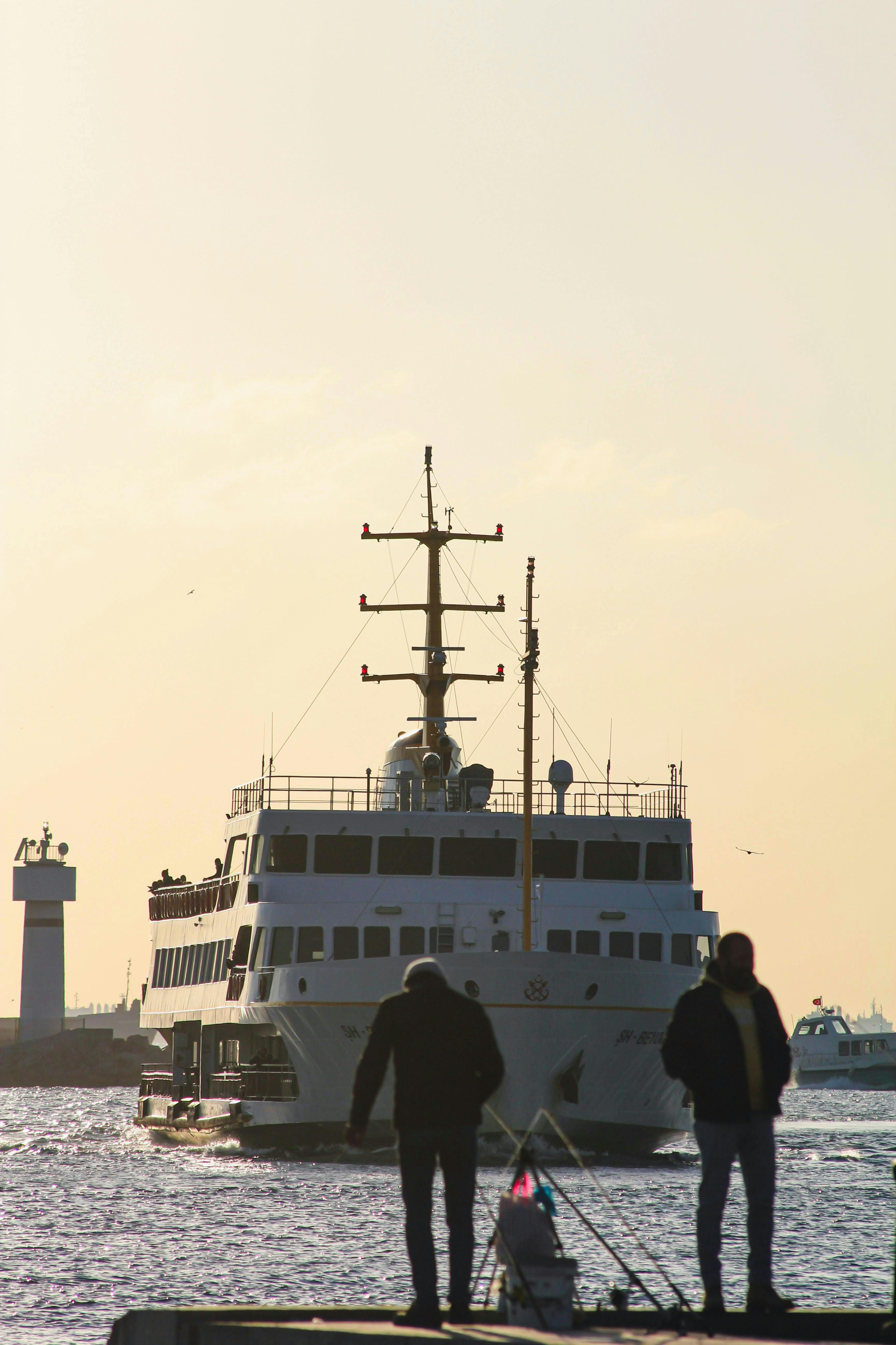 Ferry Approaching Harbor with Silhouetted Figures · Free Stock Photo