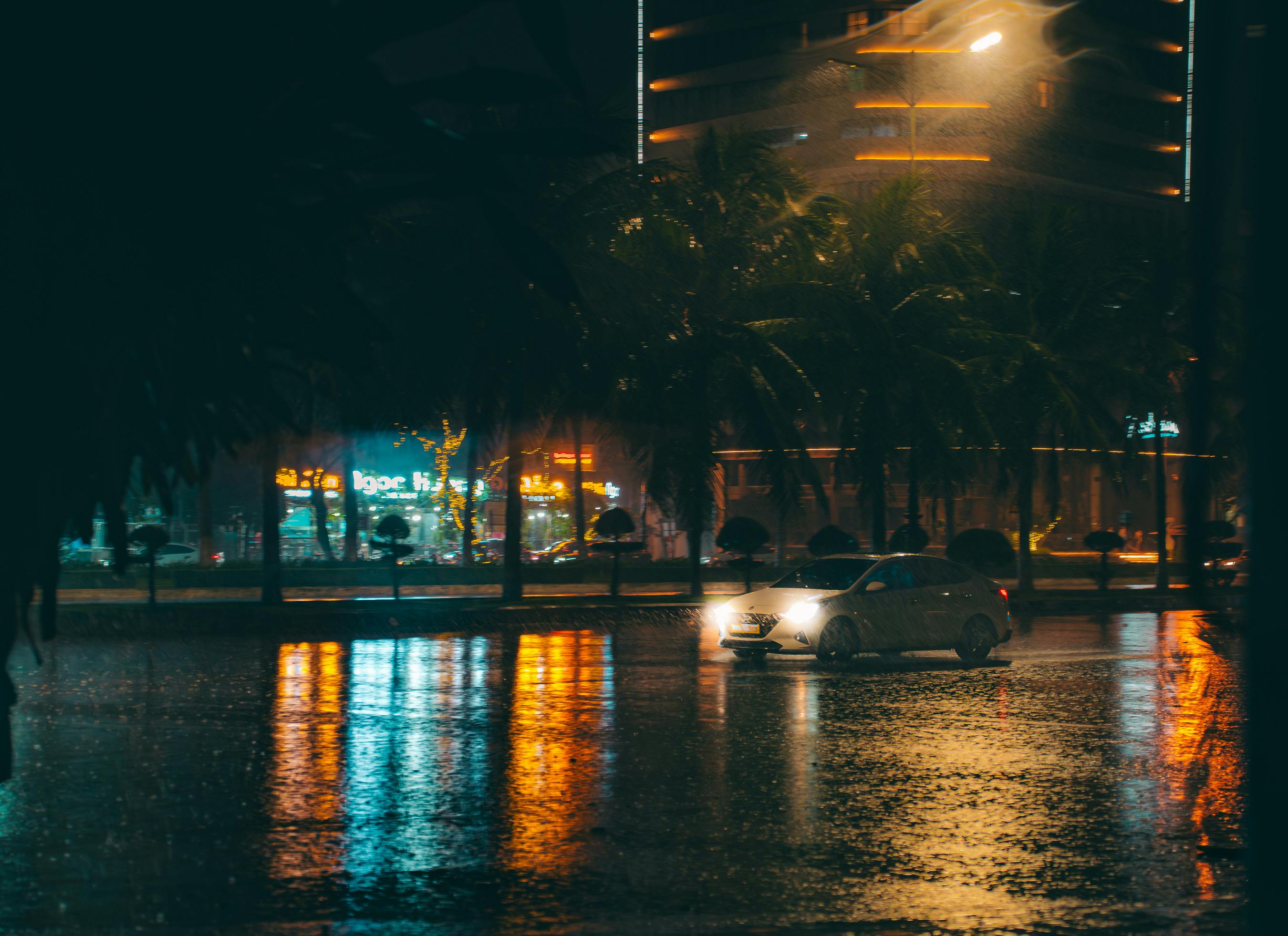 Car Driving in Rainy City at Night with Reflections · Free Stock Photo