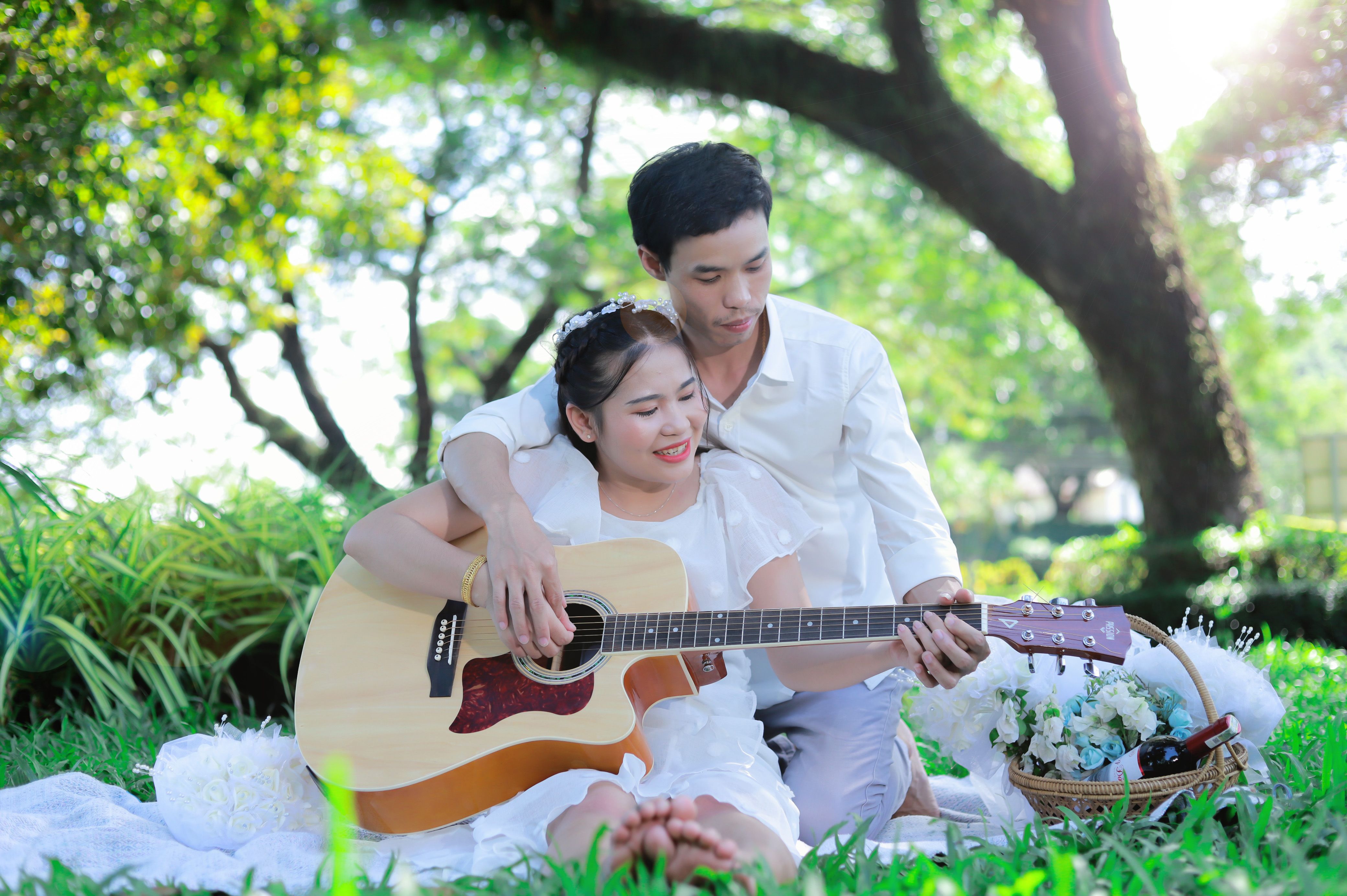 Romantic Couple Playing Guitar in Lush Park Setting · Free Stock Photo