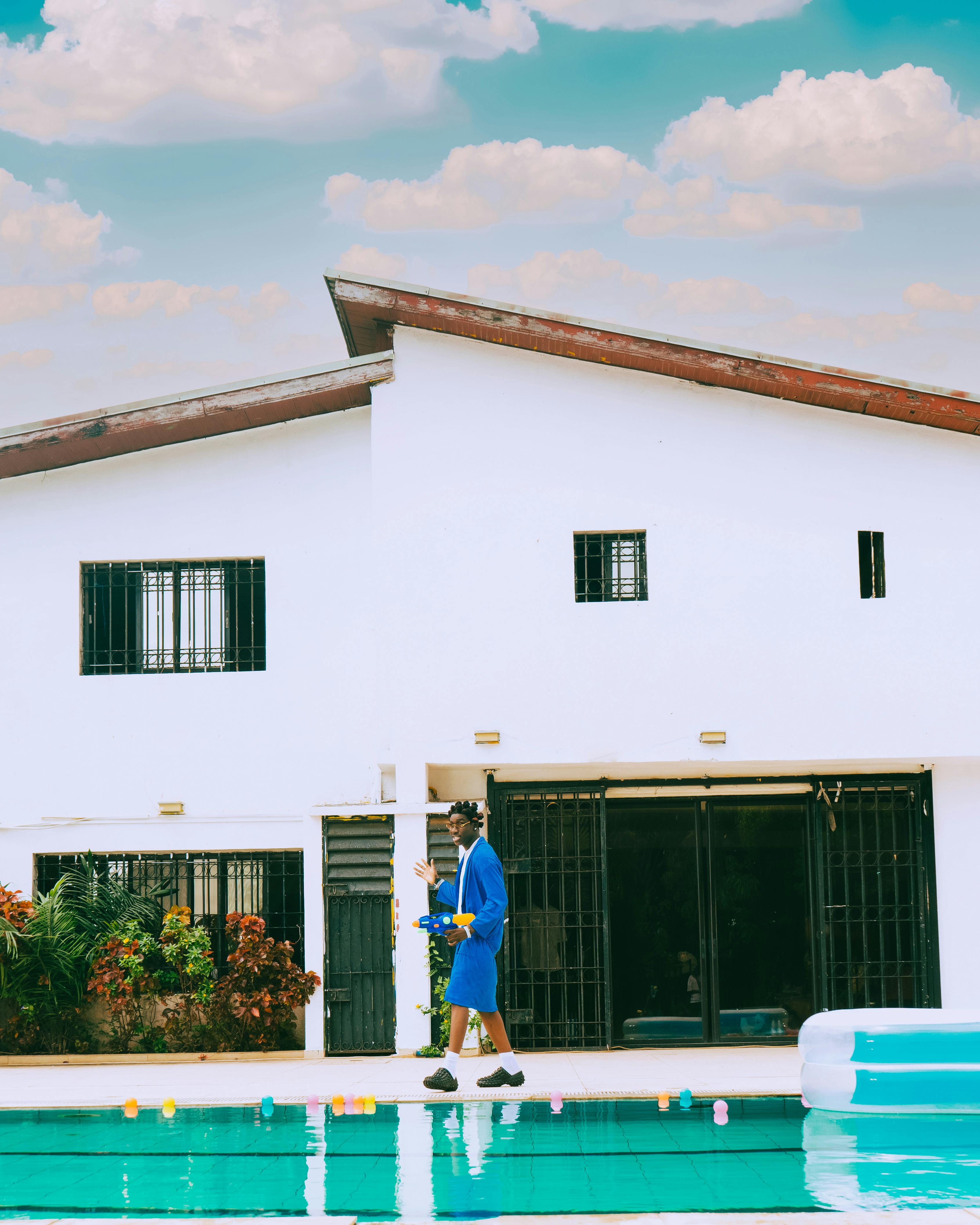 Man in Blue Suit Walking by Poolside House · Free Stock Photo