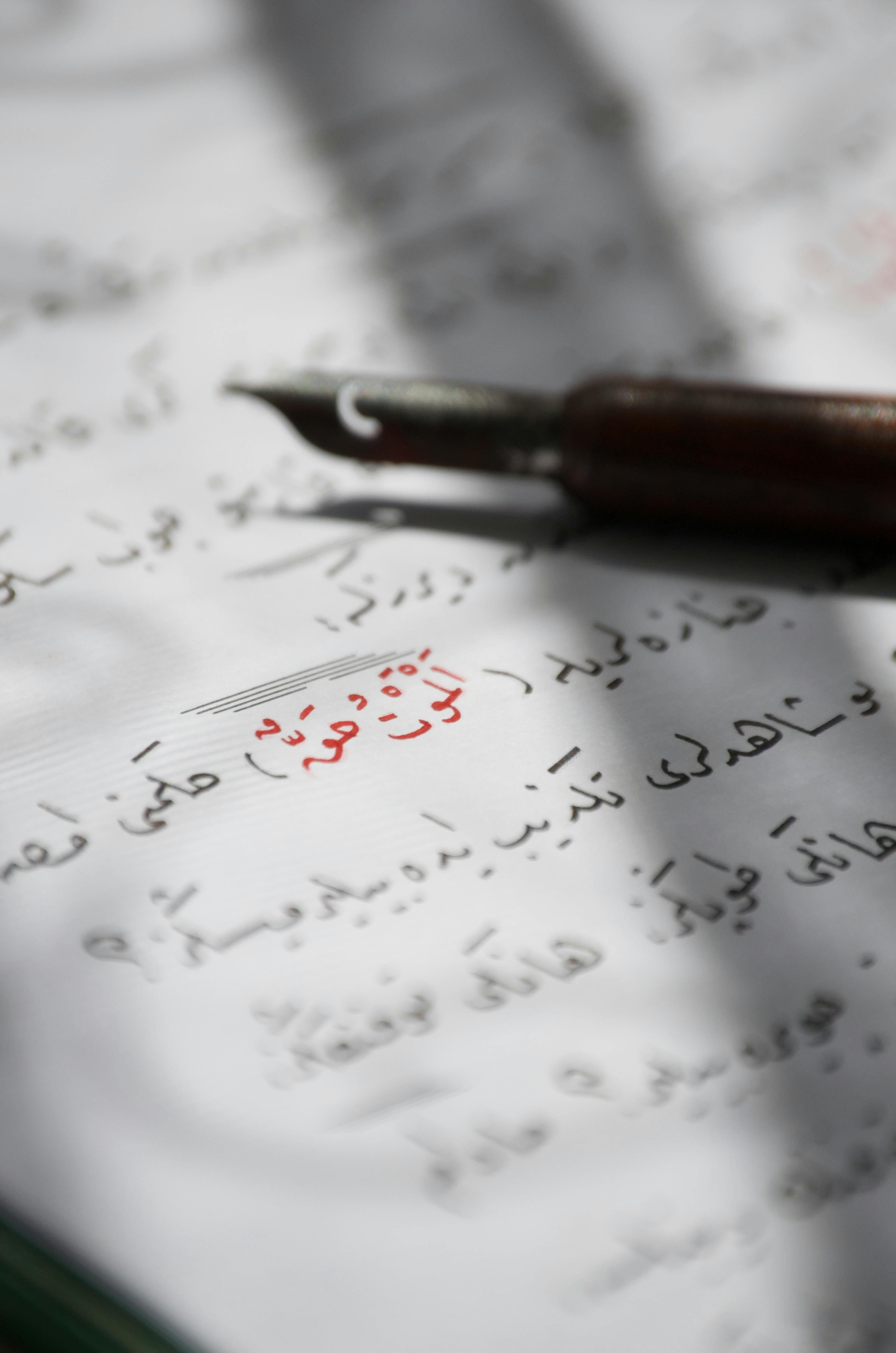 Elegant Fountain Pen Lying on Arabic Text Page · Free Stock Photo