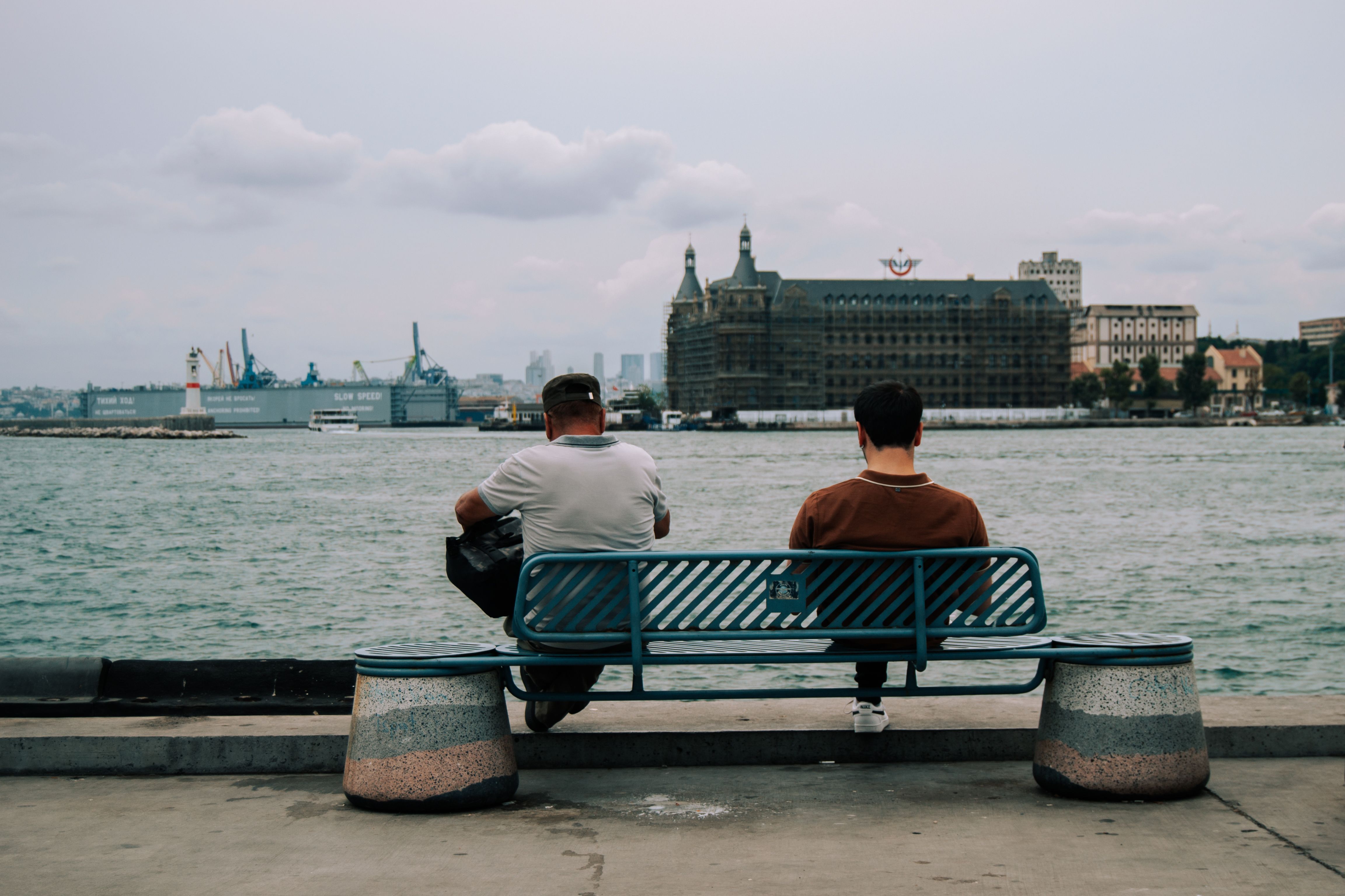 Two Men Sitting on Bench Overlooking Haydarpaşa Terminal · Free Stock Photo