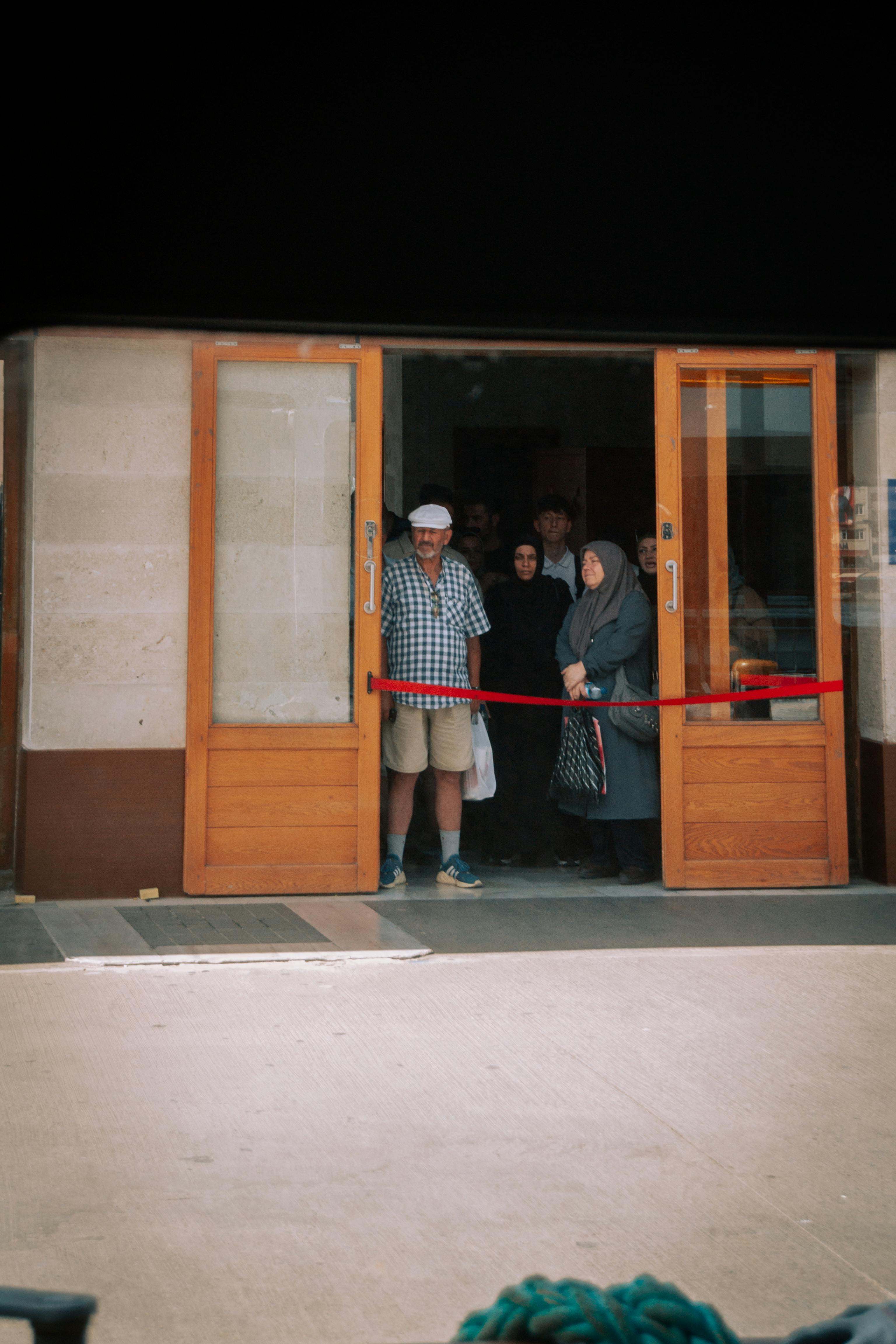 Group of People Waiting Behind Glass Doors · Free Stock Photo