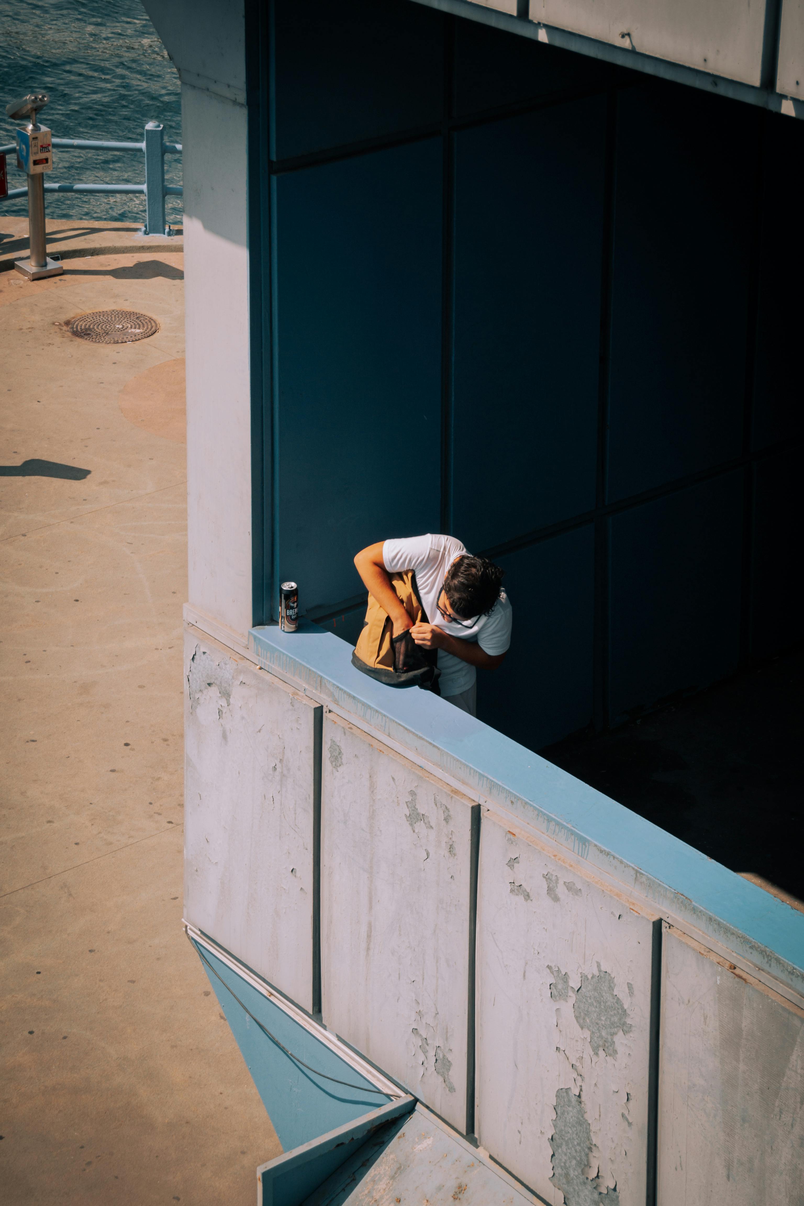 Man in Urban Setting Seated by Industrial Structure · Free Stock Photo