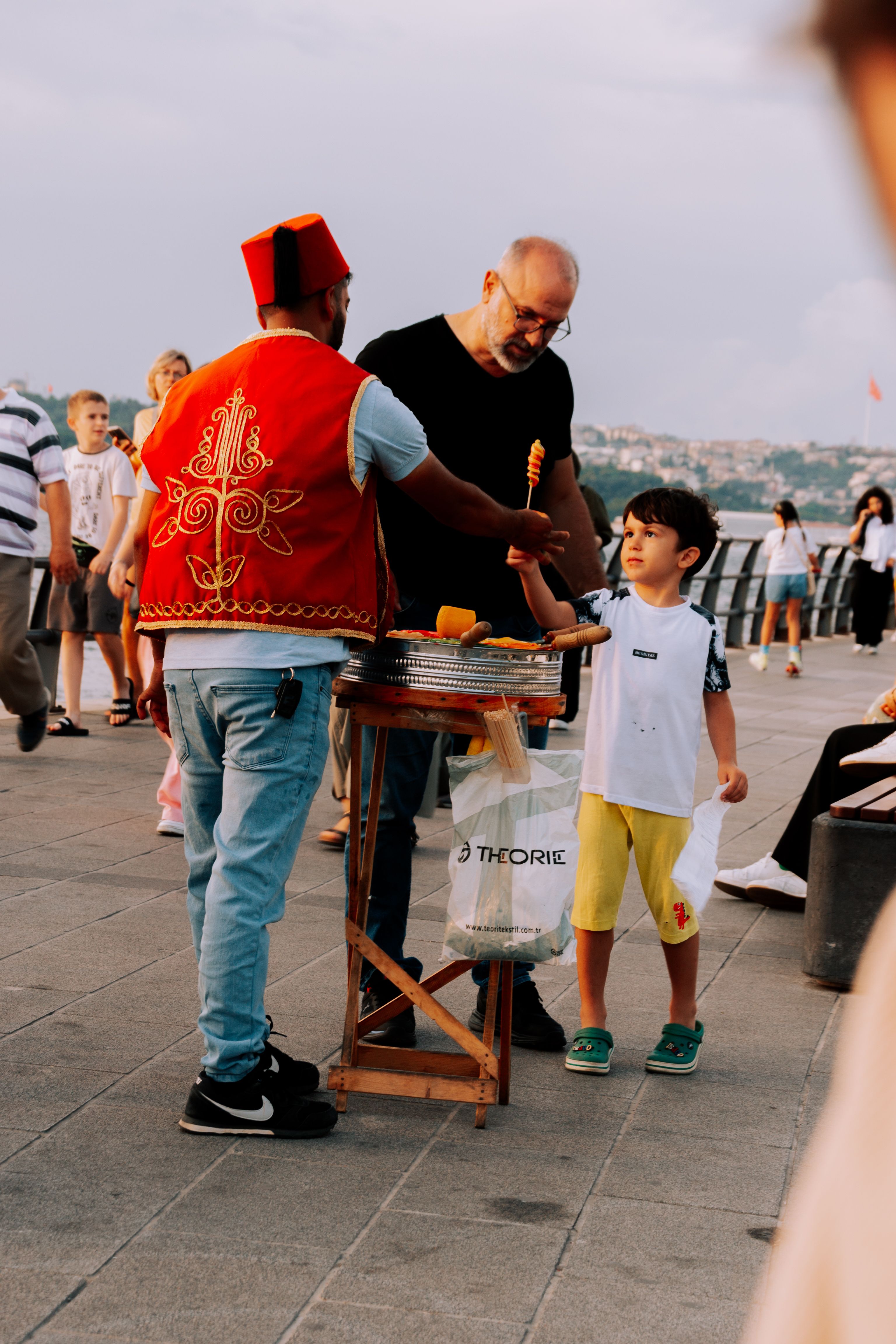 Street Food Vendor Serving Child at Seaside Promenade · Free Stock Photo