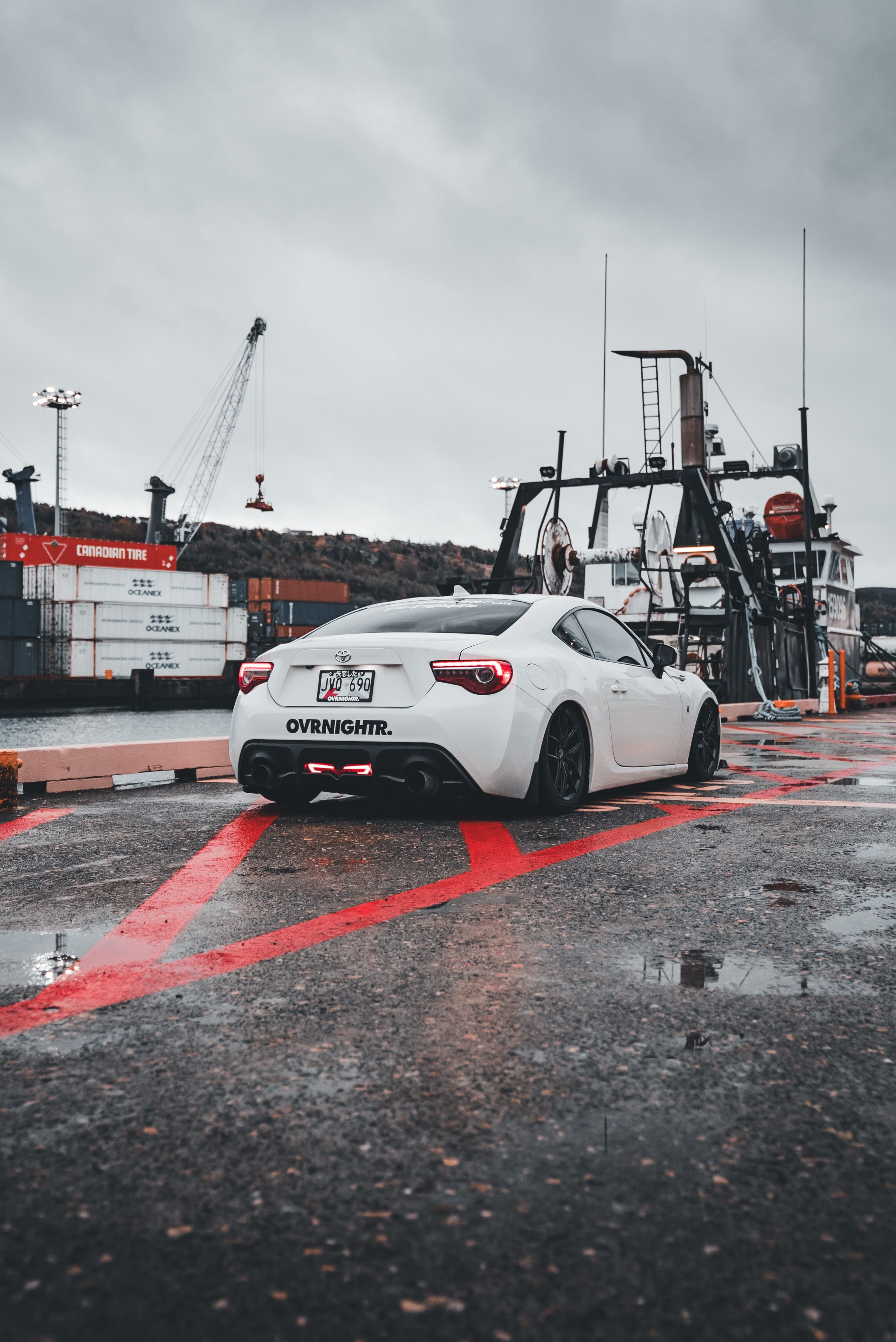 Sporty White Car at Industrial Dock with Cranes · Free Stock Photo