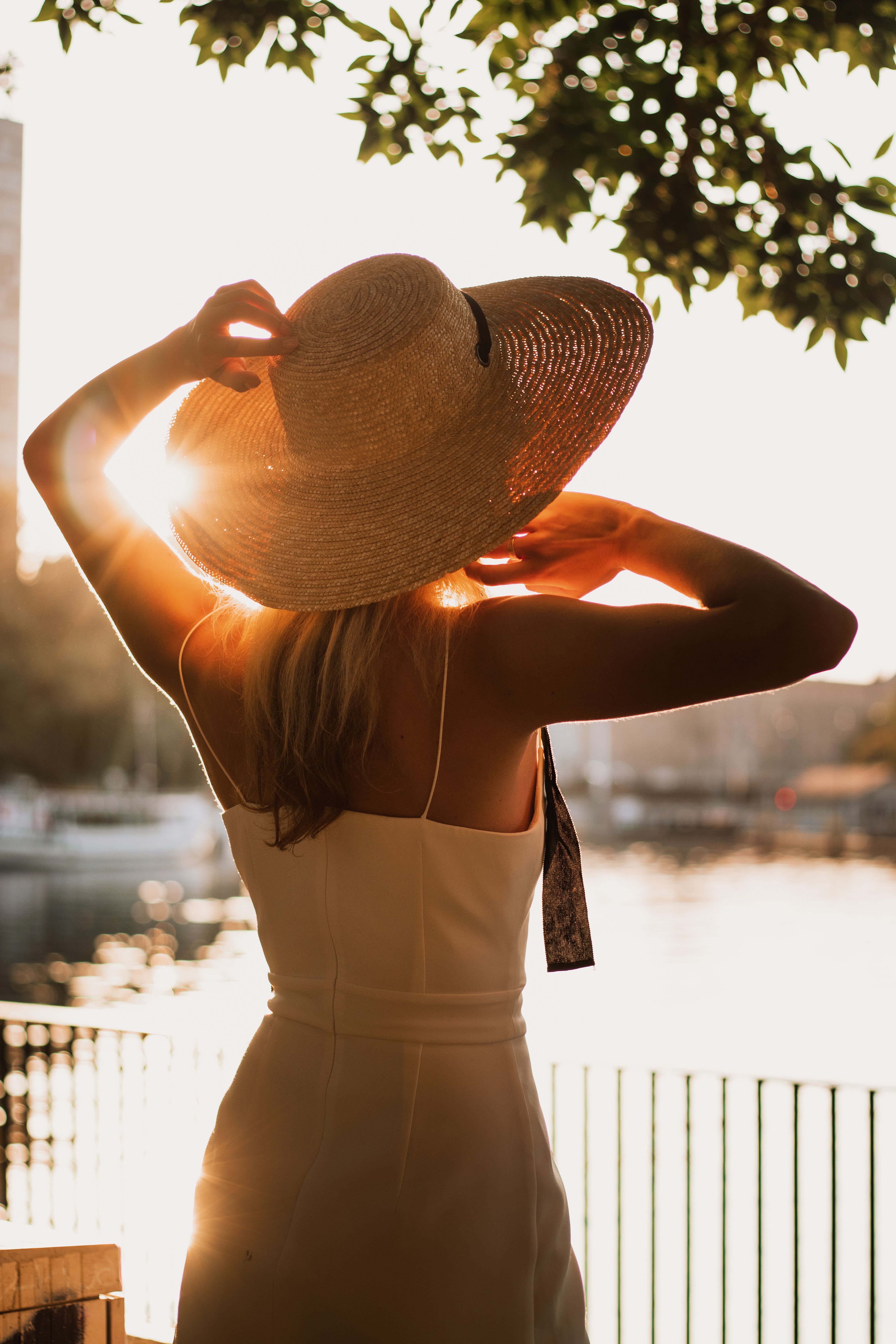 Woman in Sun Hat by River at Sunset · Free Stock Photo