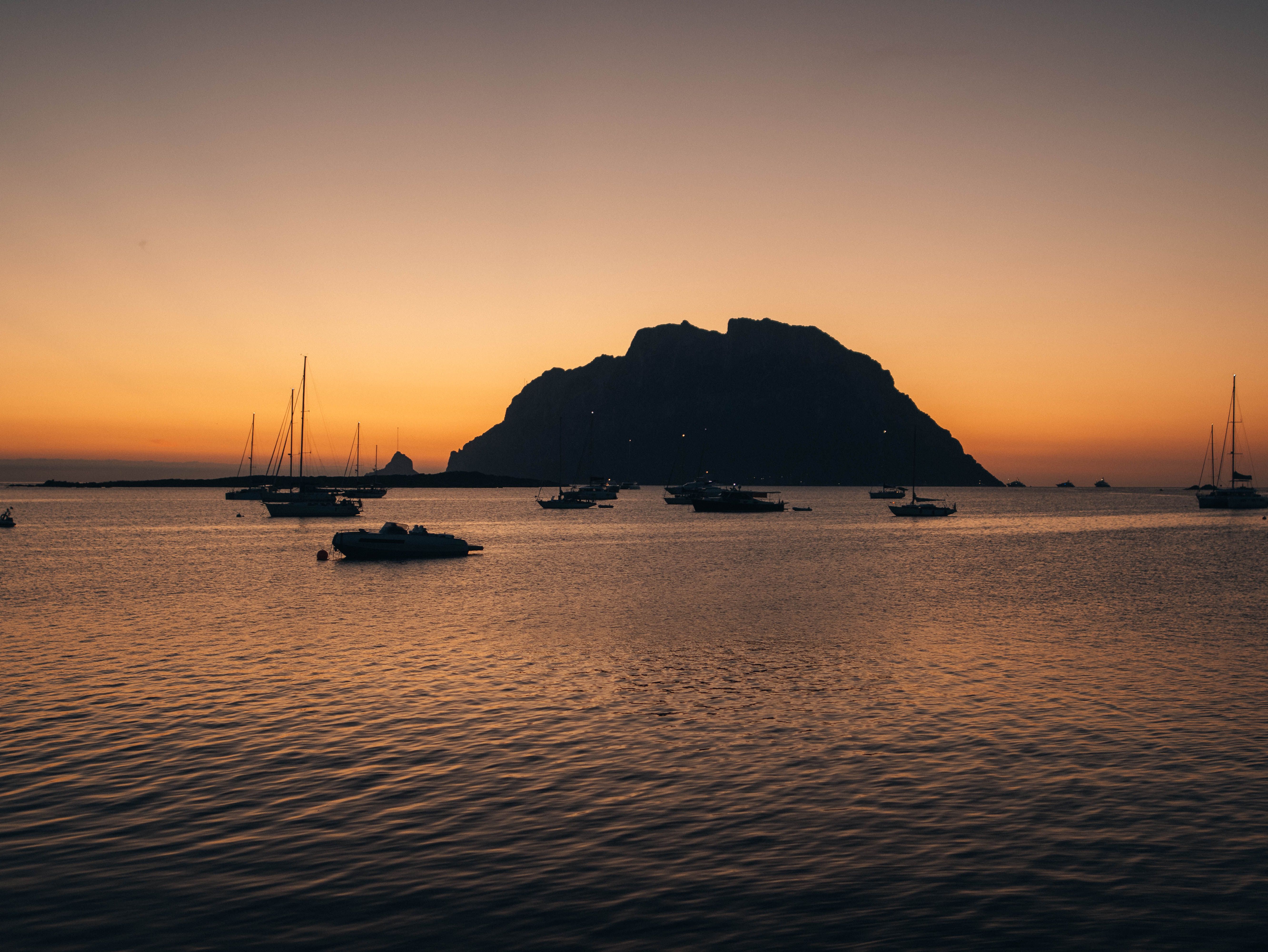 Serene Sunset Over Calm Ocean with Boats · Free Stock Photo