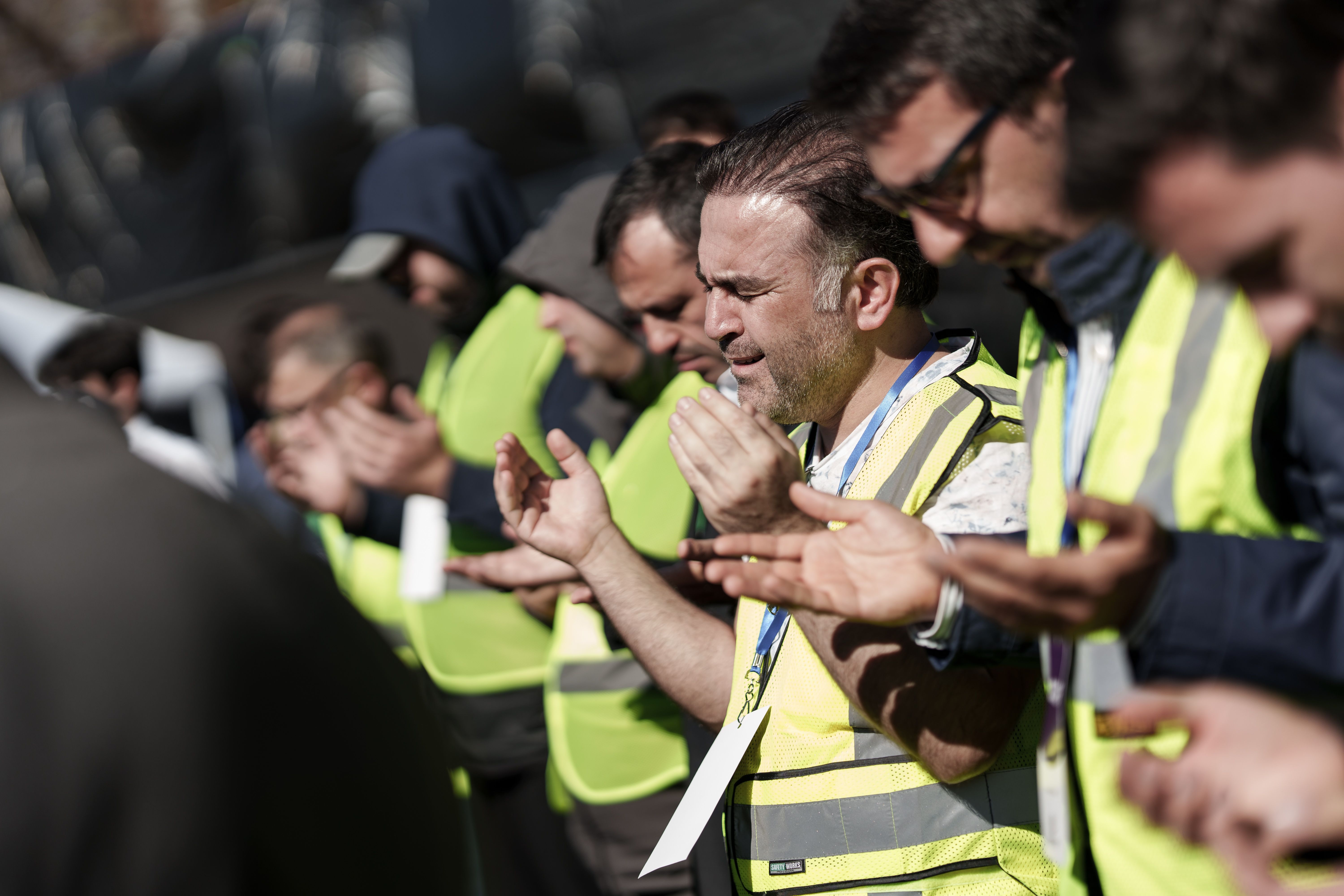 Group of Men in High-Visibility Vests Praying Outdoors · Free Stock Photo