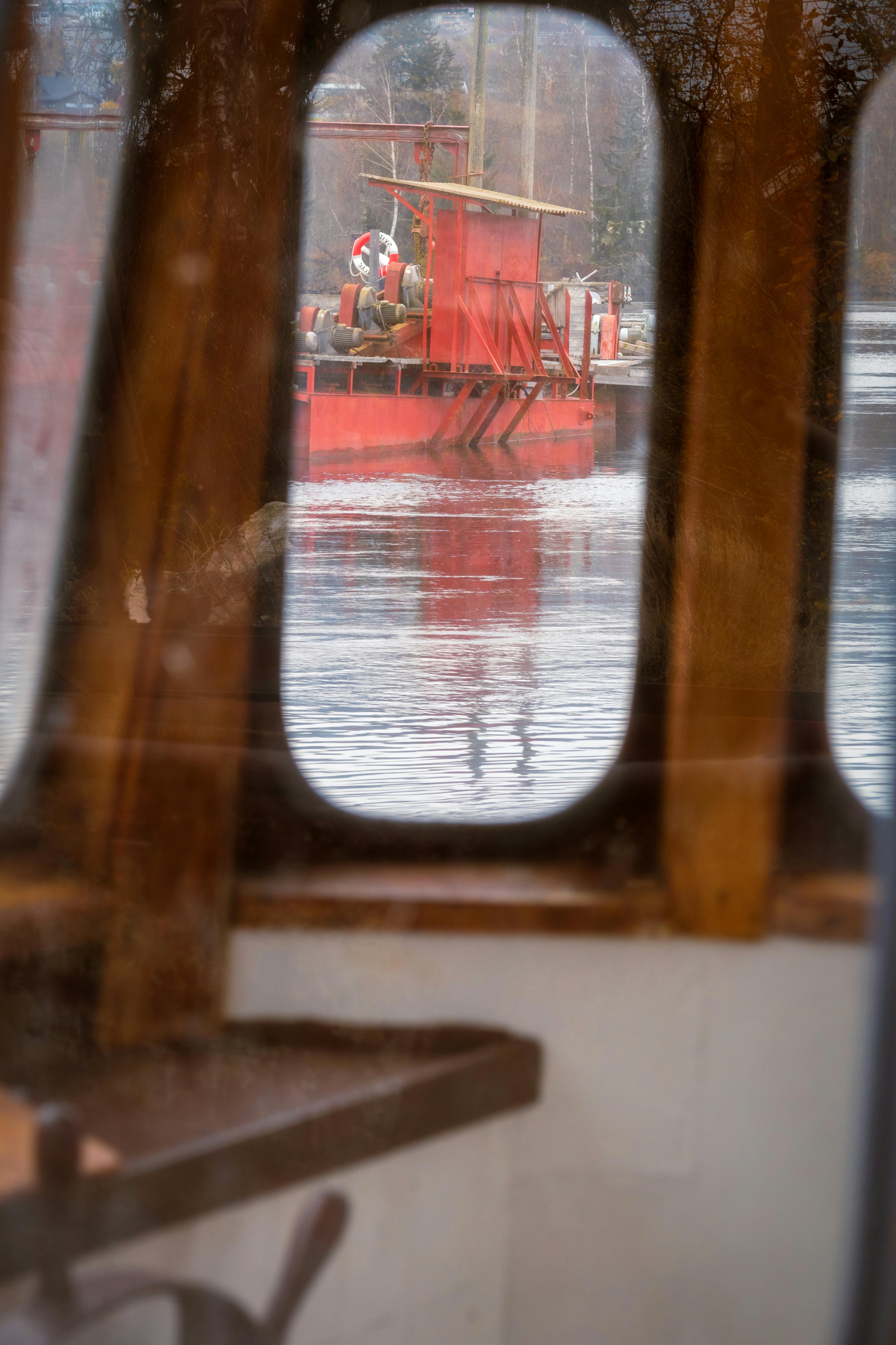View of Red Boat Through Cabin Window on River · Free Stock Photo