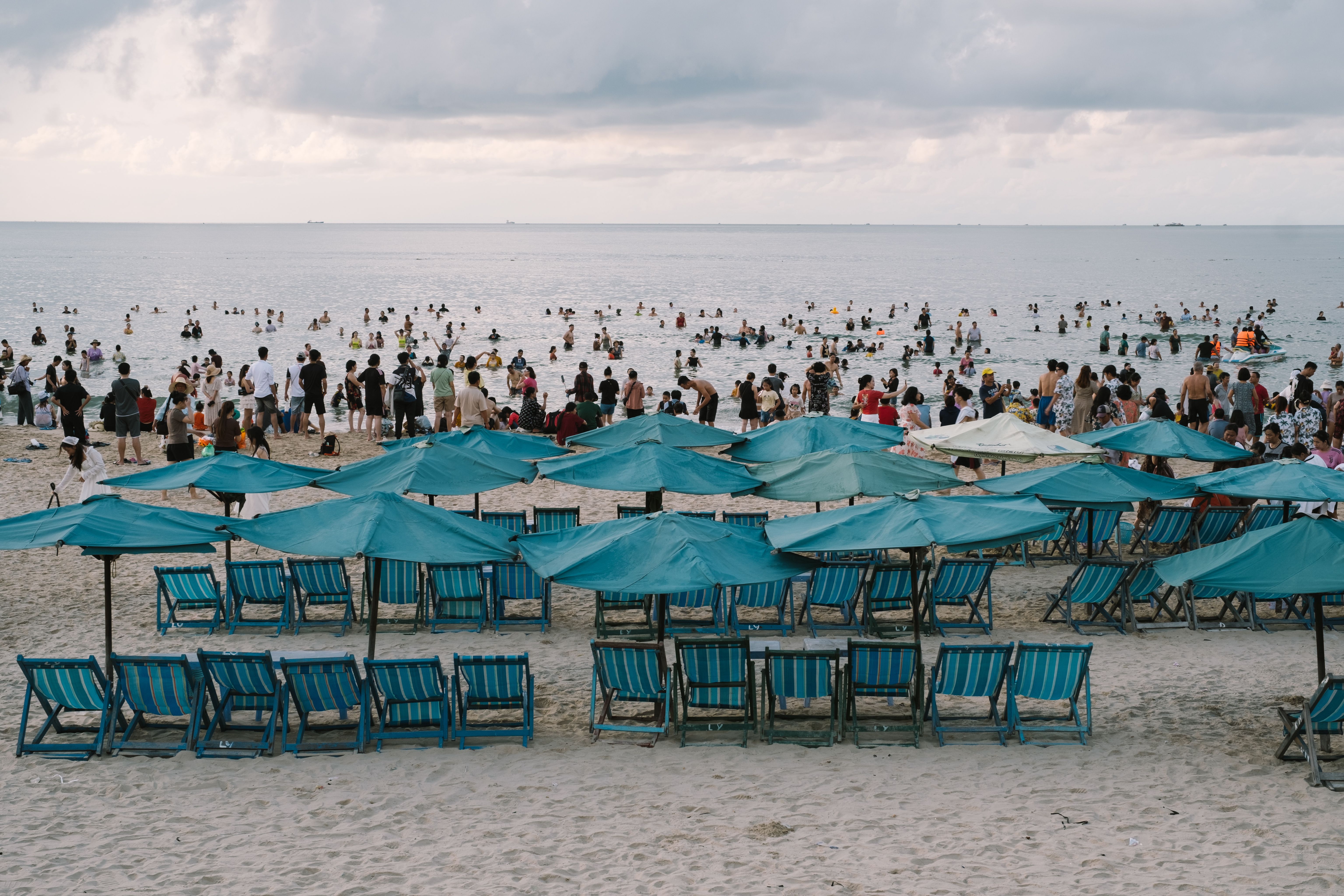 Praia Lotada Com Guarda Sóis E Cadeiras Azuis · Foto profissional gratuita