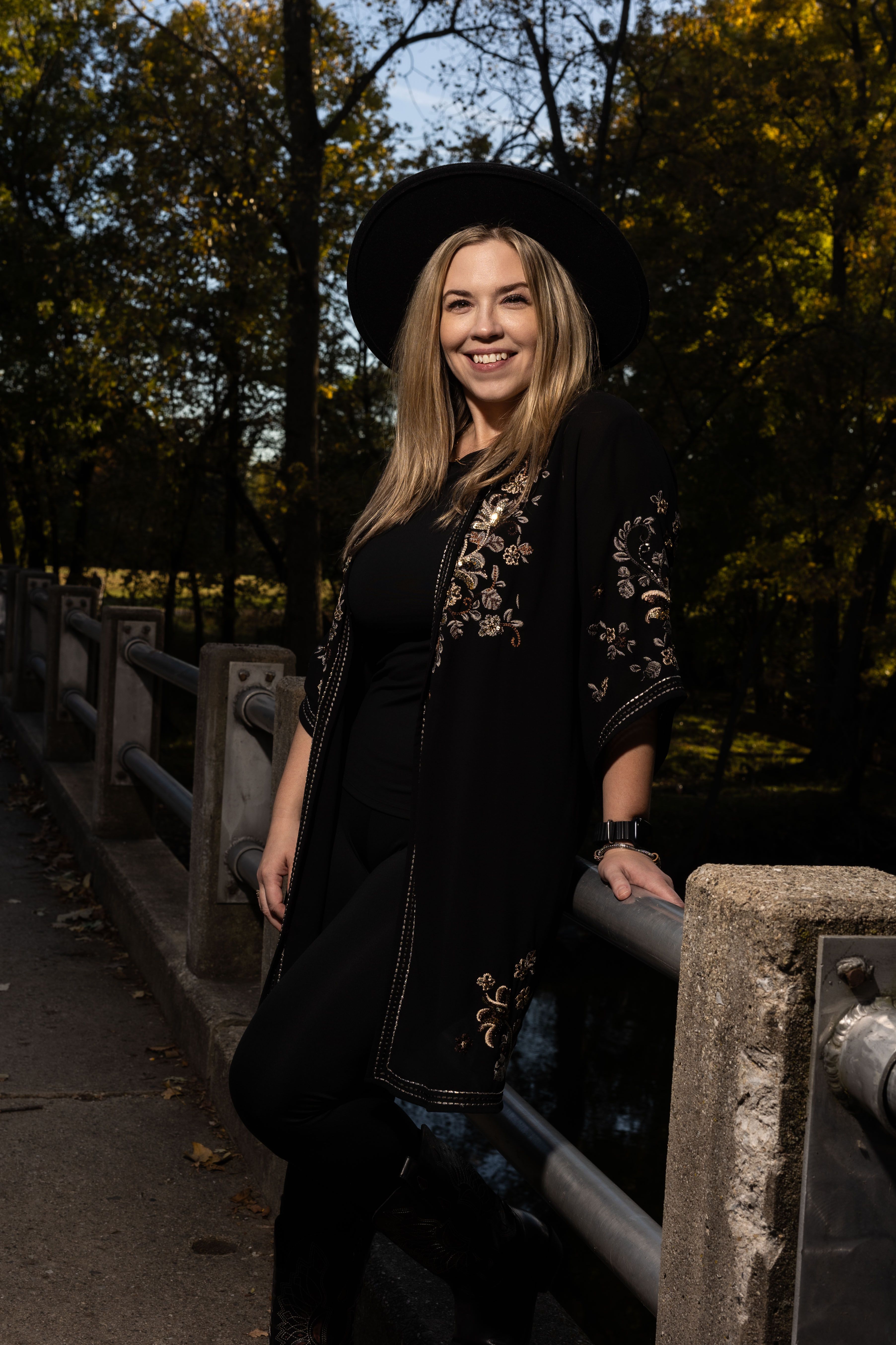 Smiling Woman in Embroidered Outfit on Bridge · Free Stock Photo
