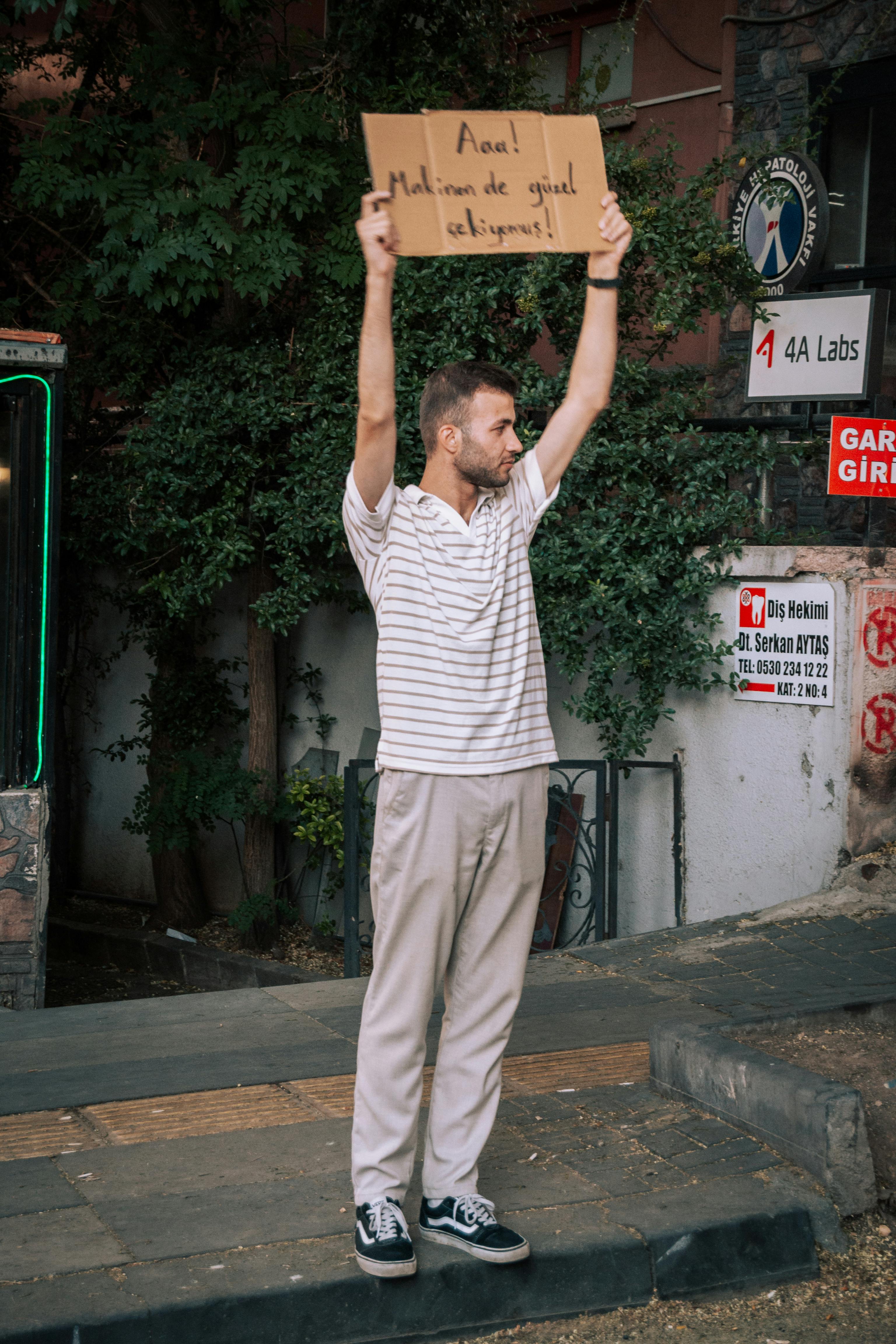 Person Holding Sign on Urban Street · Free Stock Photo