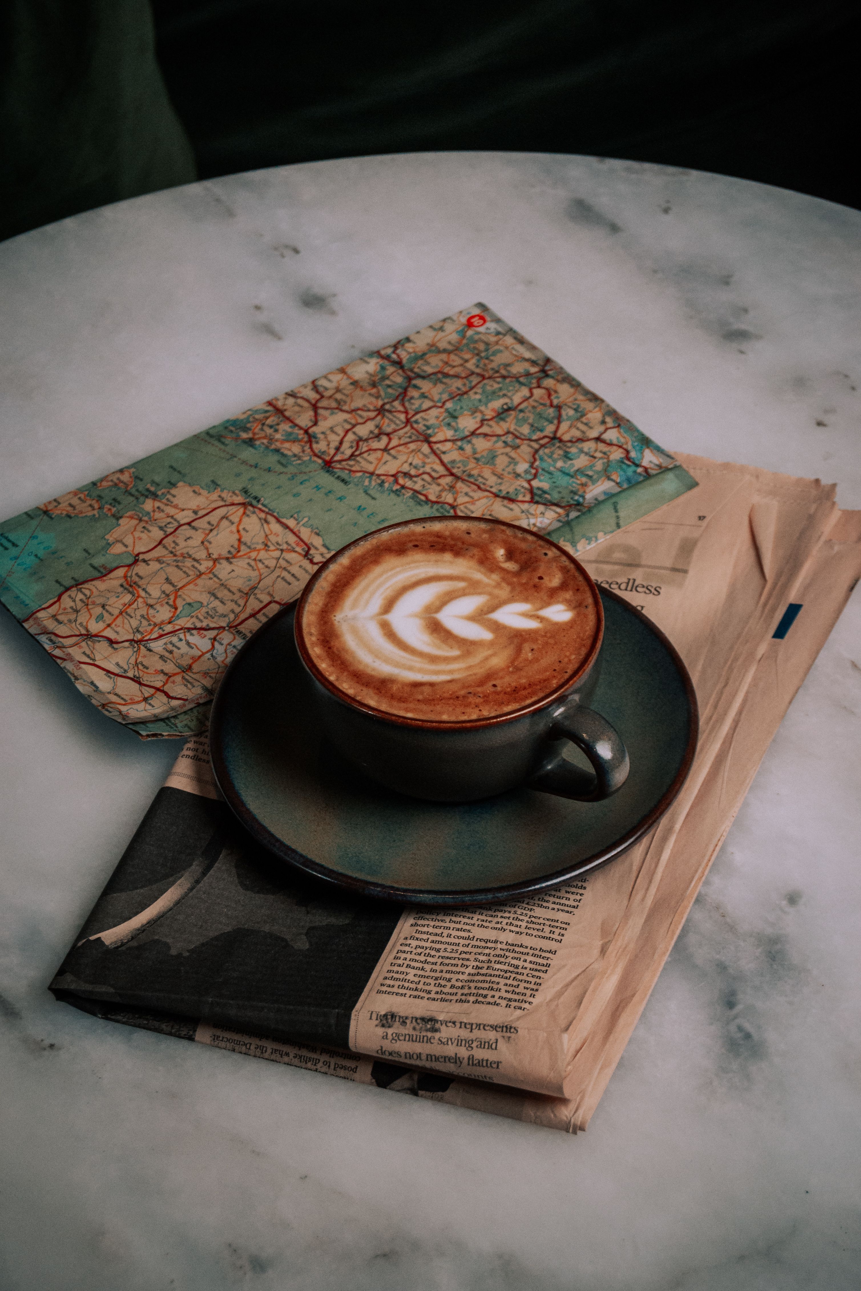 Artful Latte with Map and Newspaper on Marble Table · Free Stock Photo