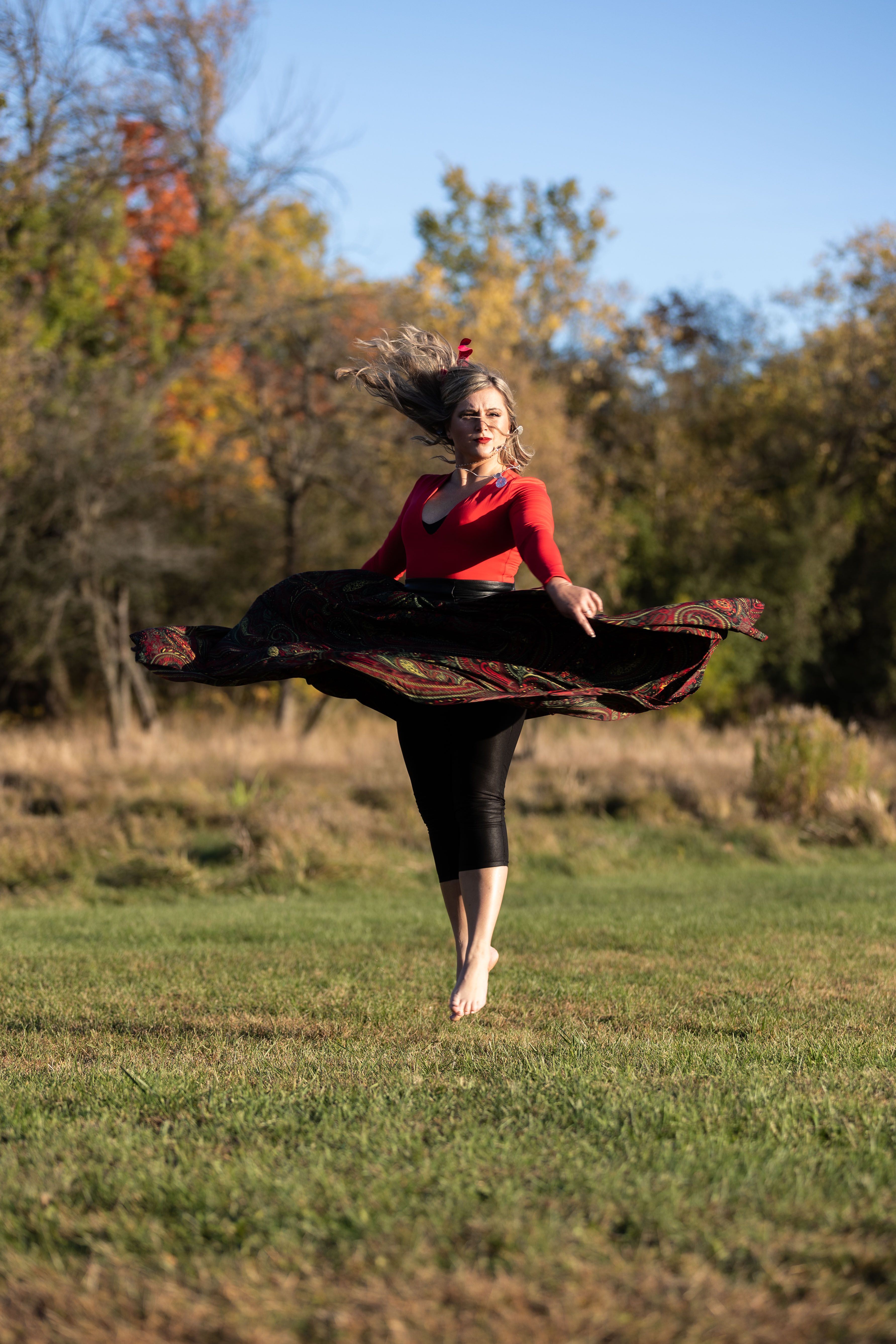 Woman Twirling in Autumn Field Under Blue Sky · Free Stock Photo
