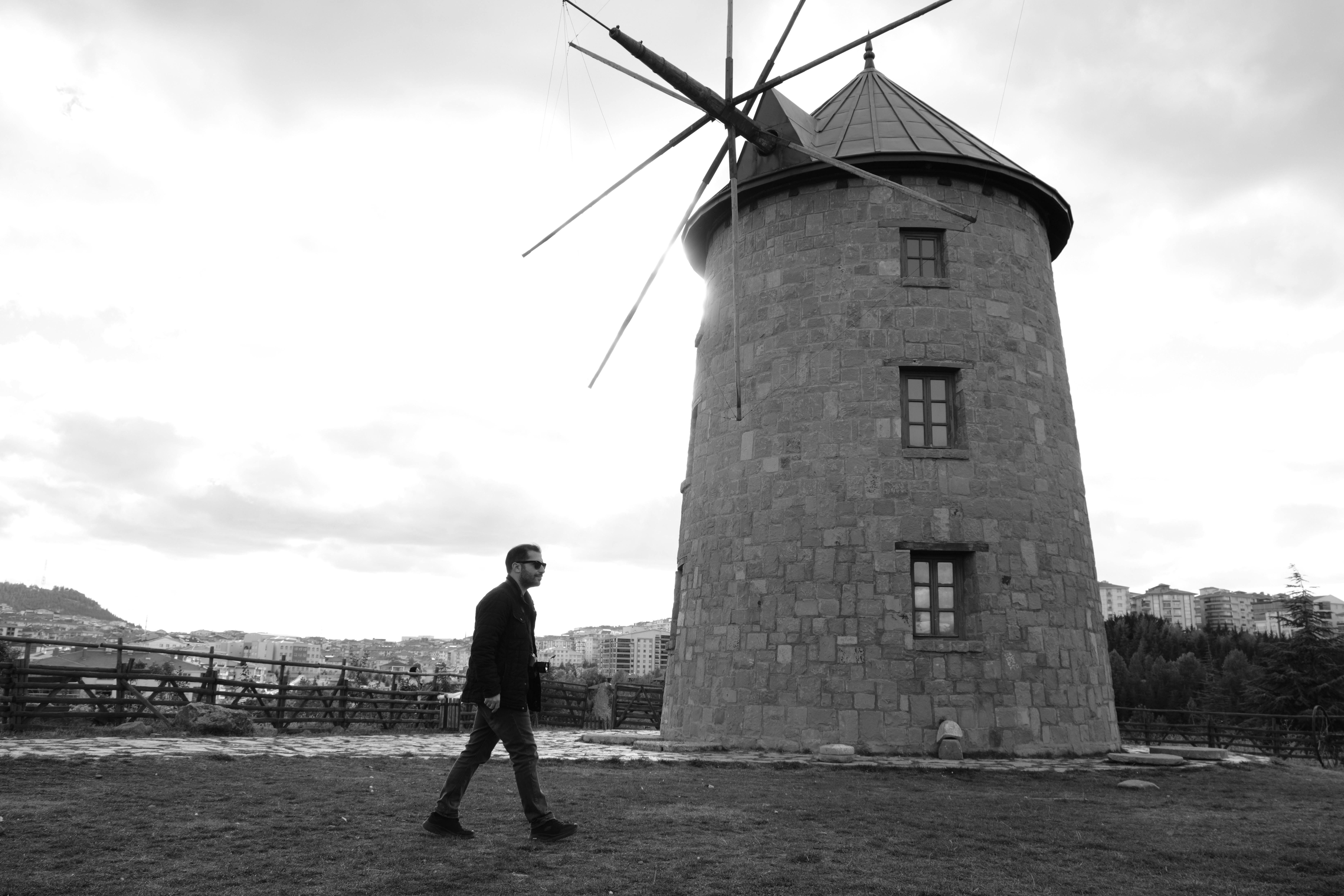 Monochrome Scene of Man Walking by Old Windmill · Free Stock Photo