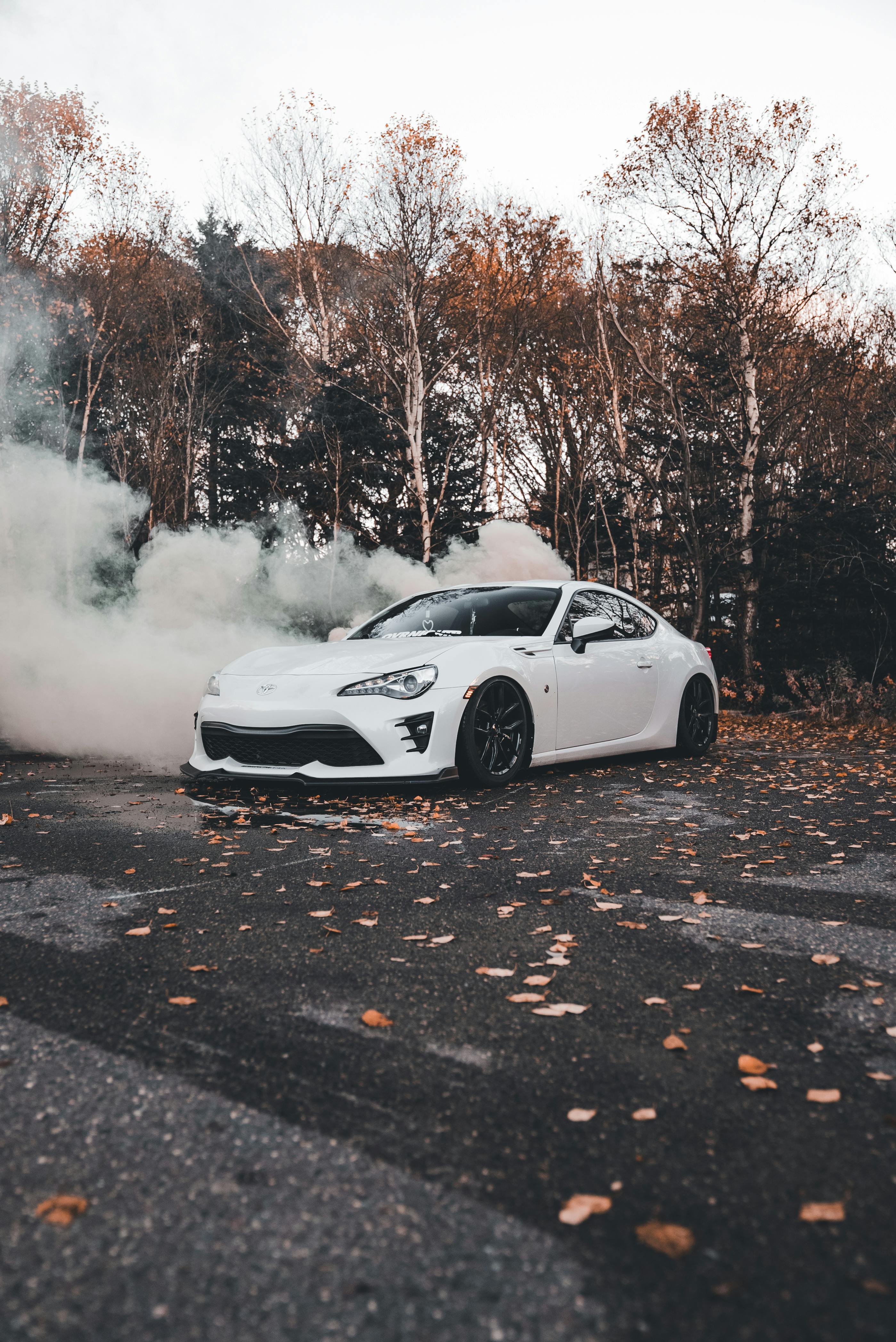 White Sports Car in Smoky Autumn Forest · Free Stock Photo