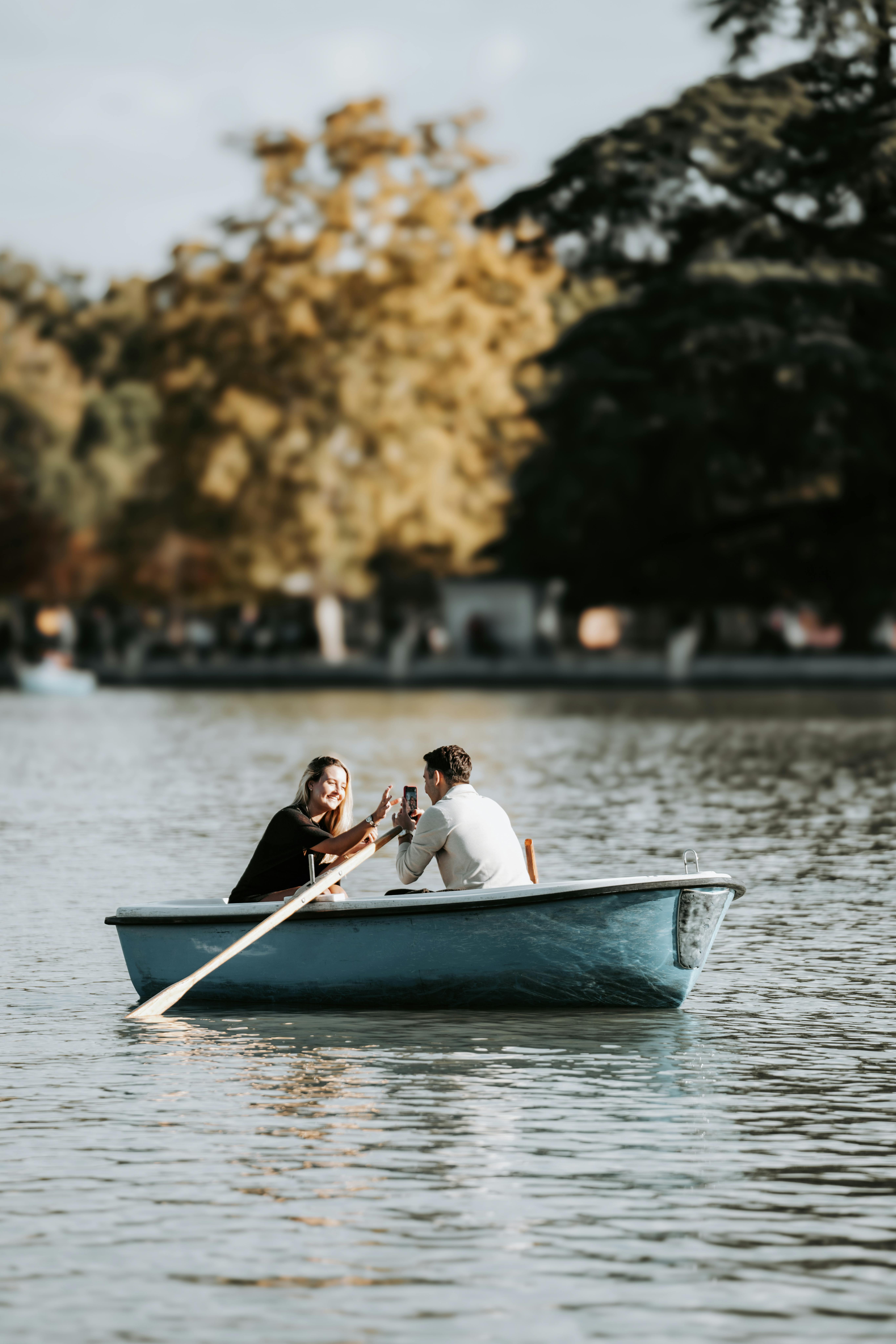 Couple Relaxing in a Blue Rowboat on a Tranquil Lake · Free Stock Photo