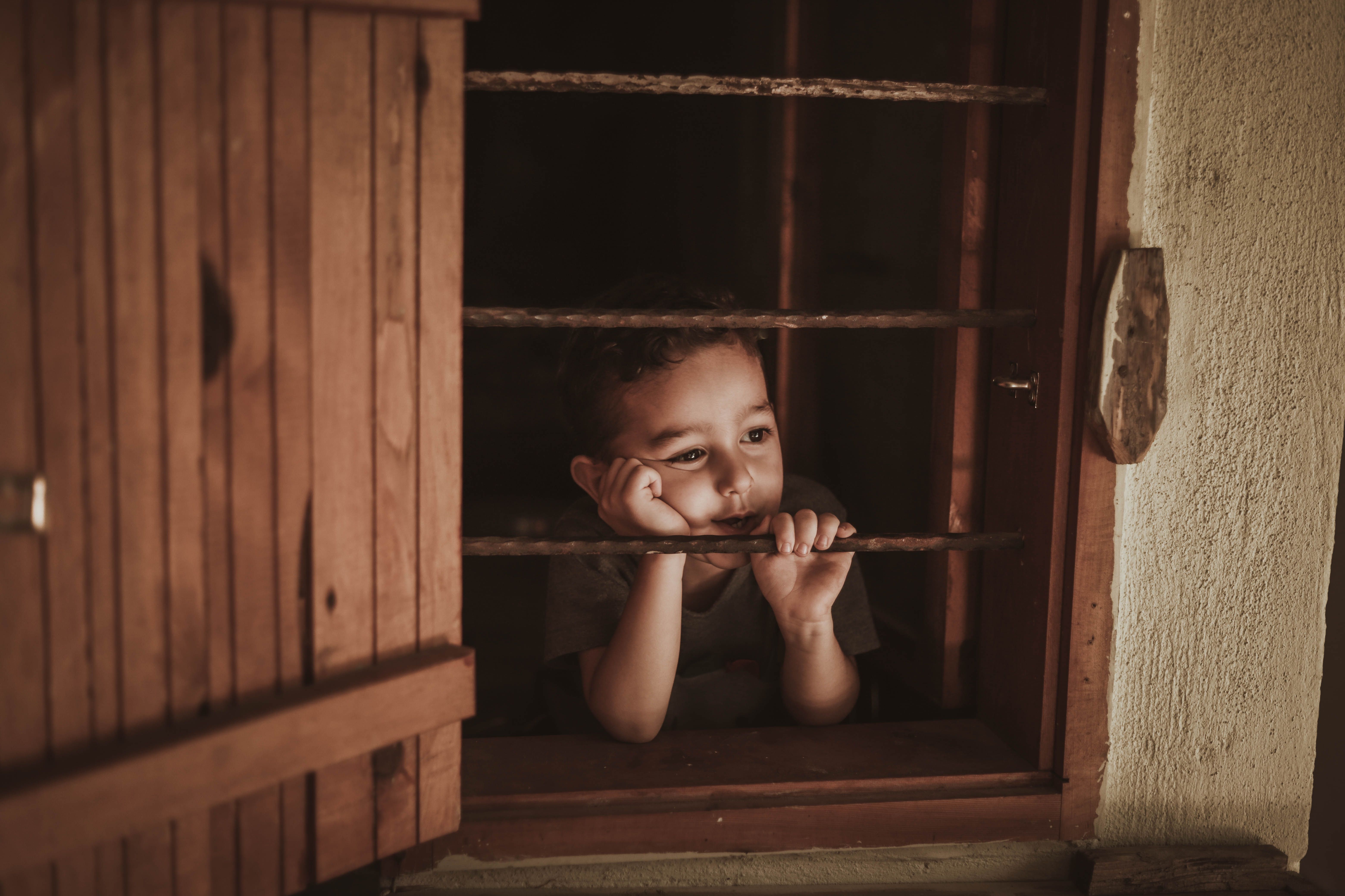 Photo Of Boy Leaning On Window Rails · Free Stock Photo