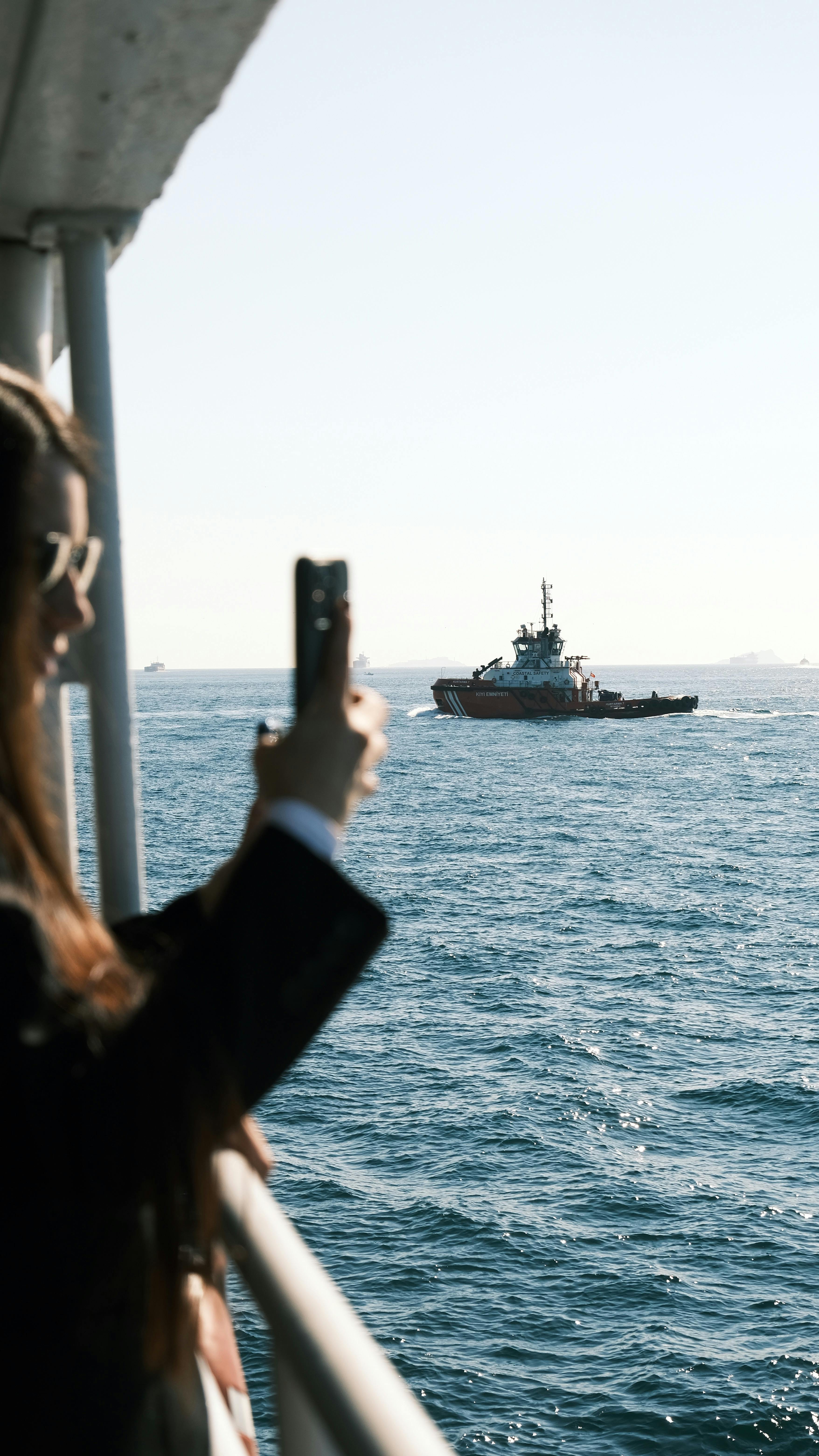 Woman Photographing Tugboat on Open Sea from Ship · Free Stock Photo