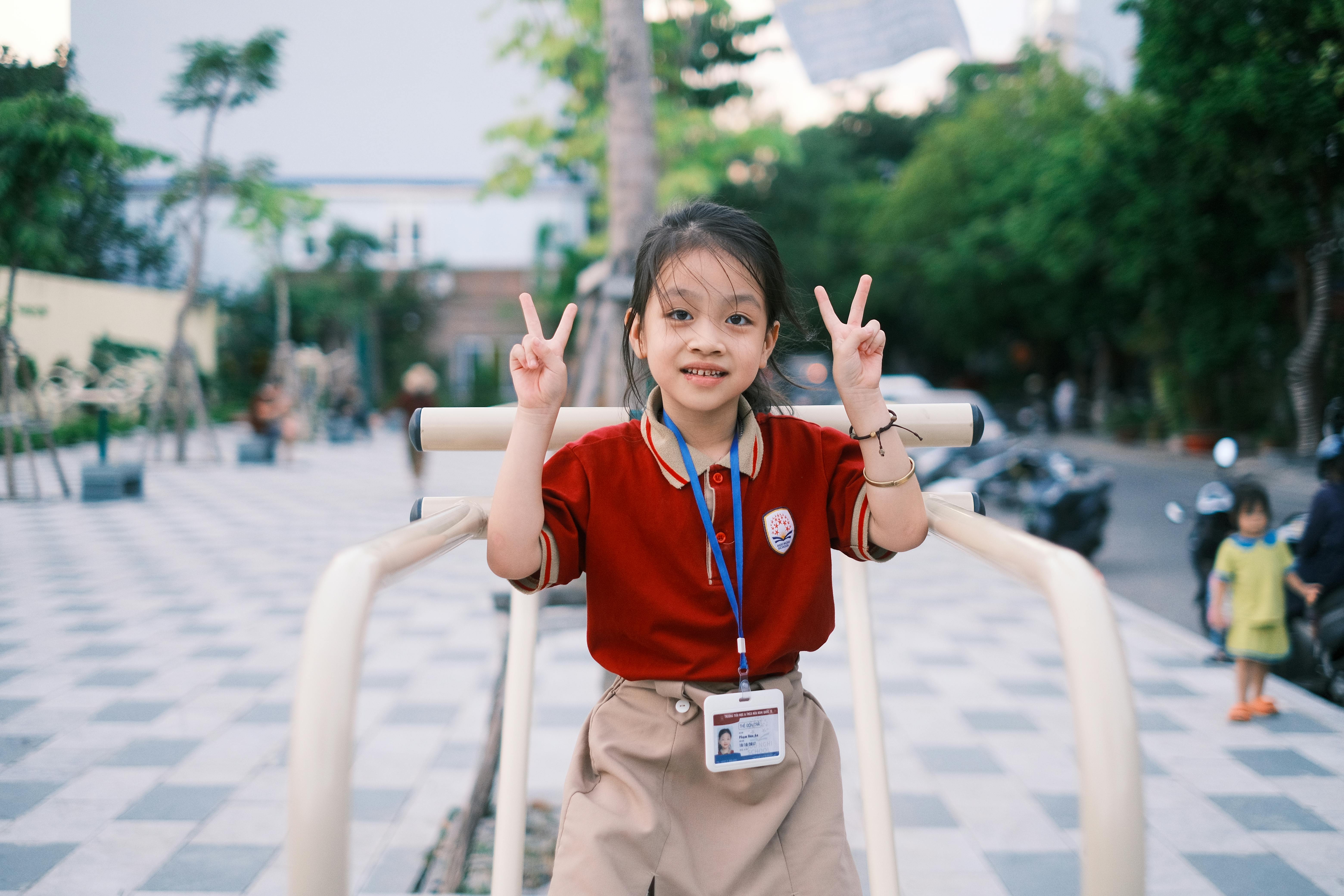 Smiling Girl Posing Outdoors with Peace Sign · Free Stock Photo