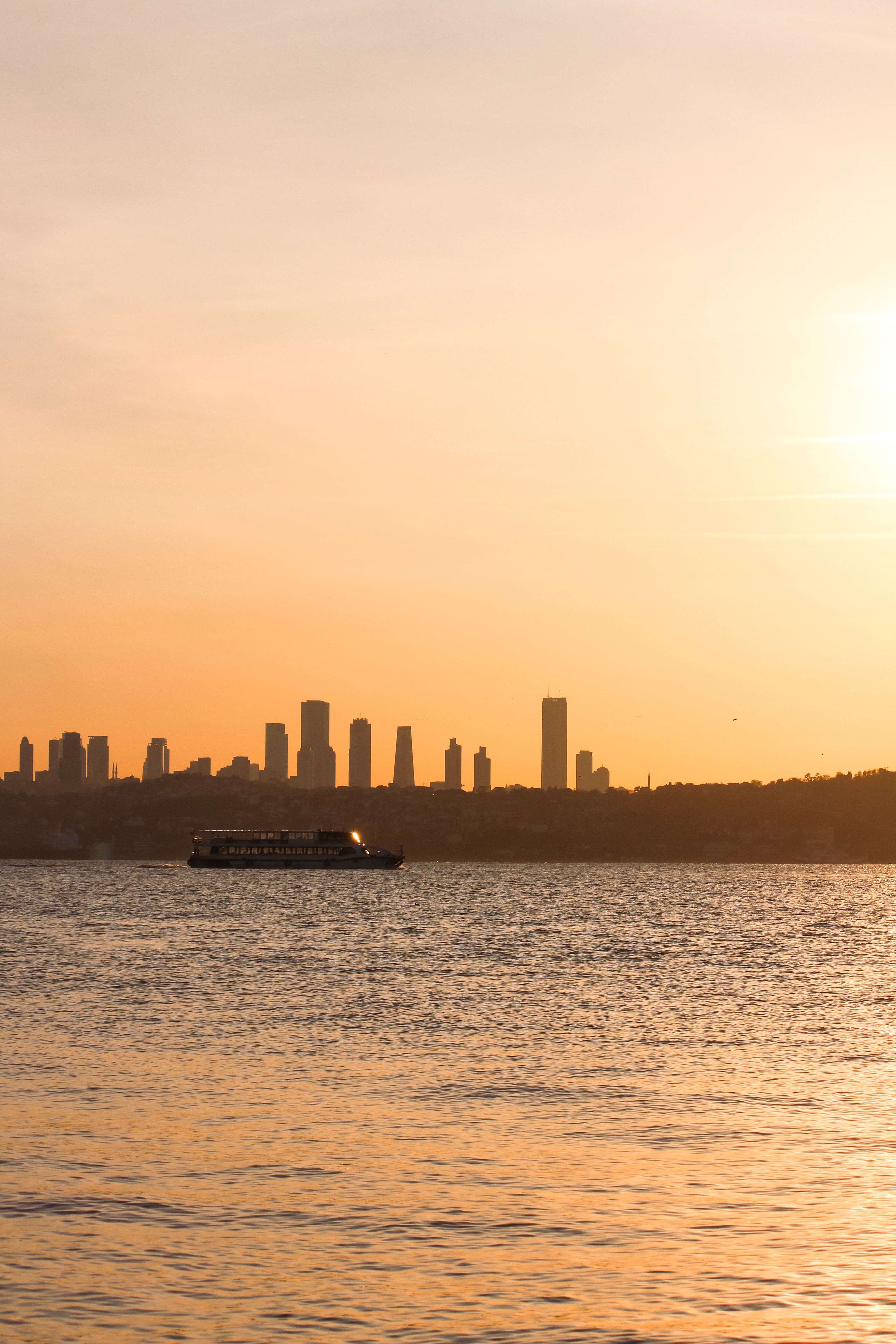 Sunset Over City Skyline with Ferry · Free Stock Photo