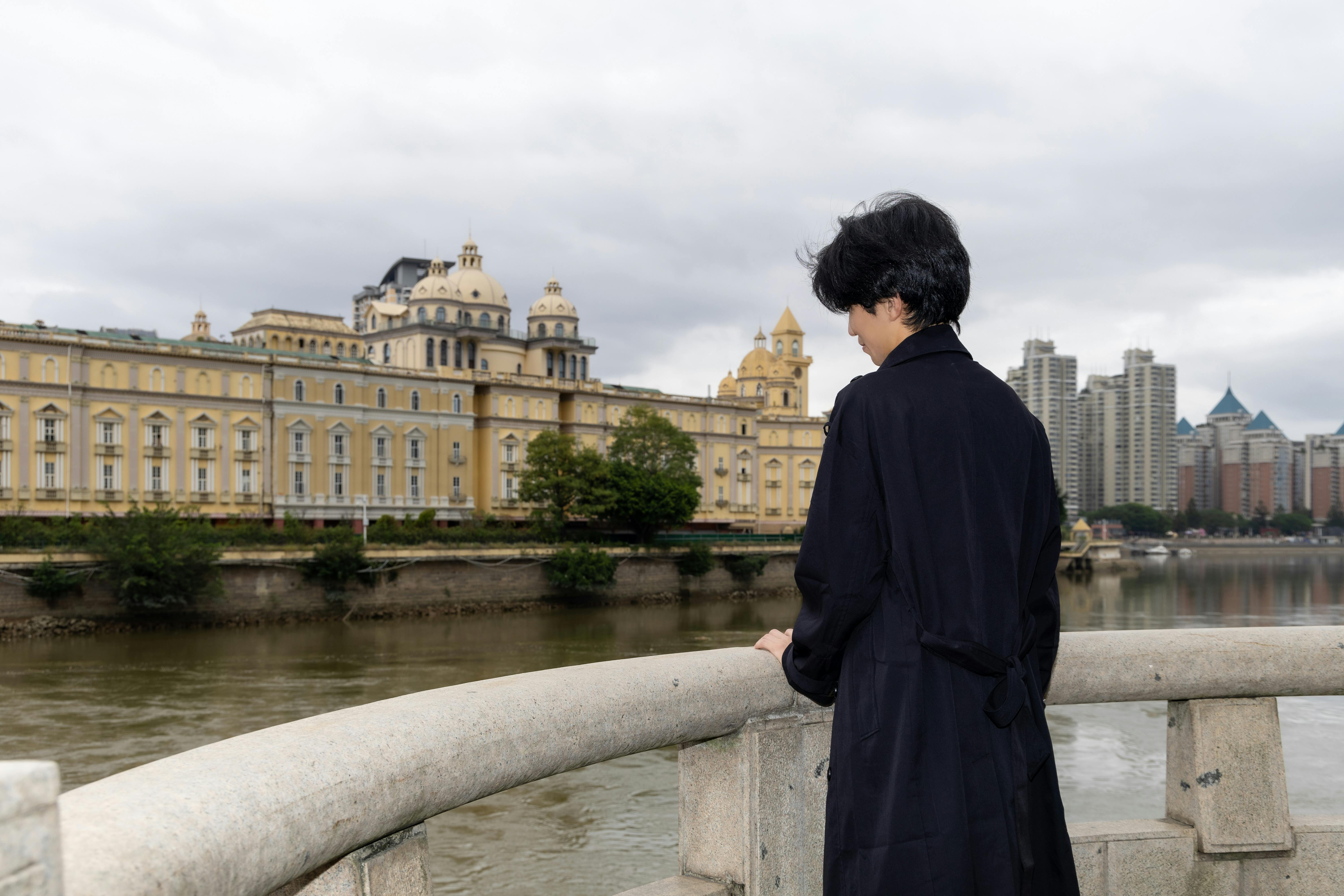 Person Standing on Bridge Overlooking Cityscape · Free Stock Photo