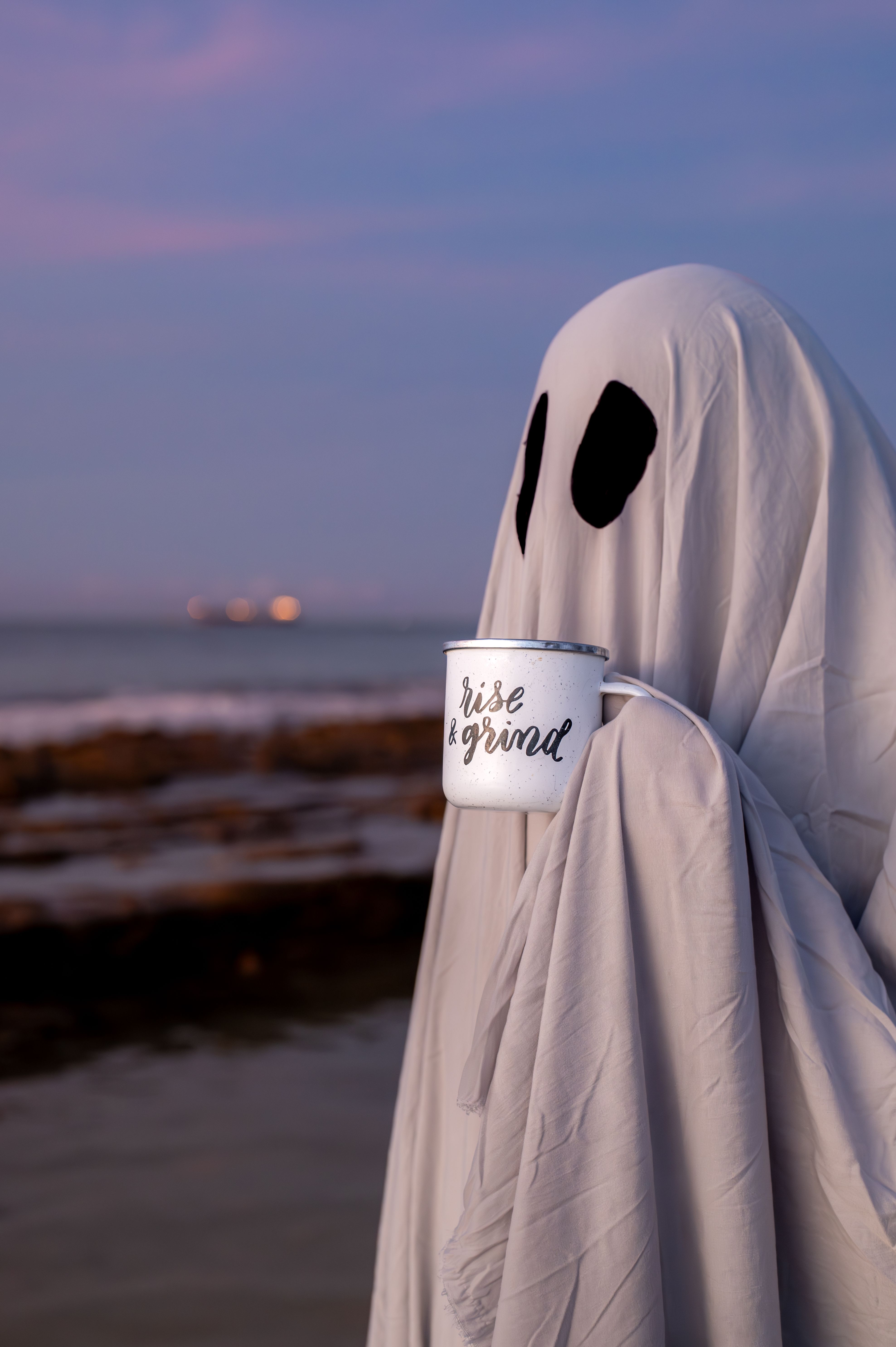 Ghost Costume on Beach with Coffee Mug at Sunrise · Free Stock Photo