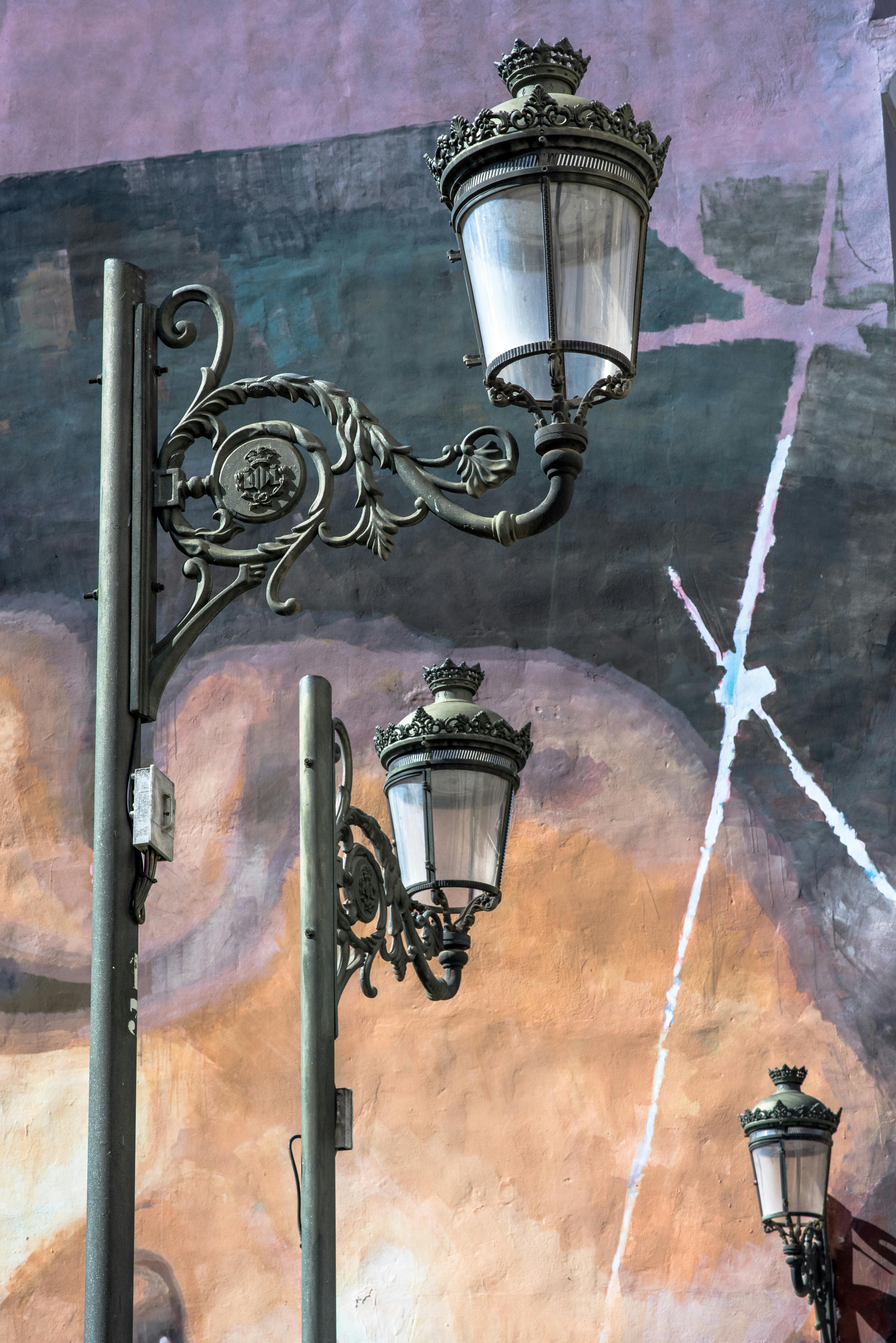 Ornate Street Lamps Against Artistic Wall Mural · Free Stock Photo