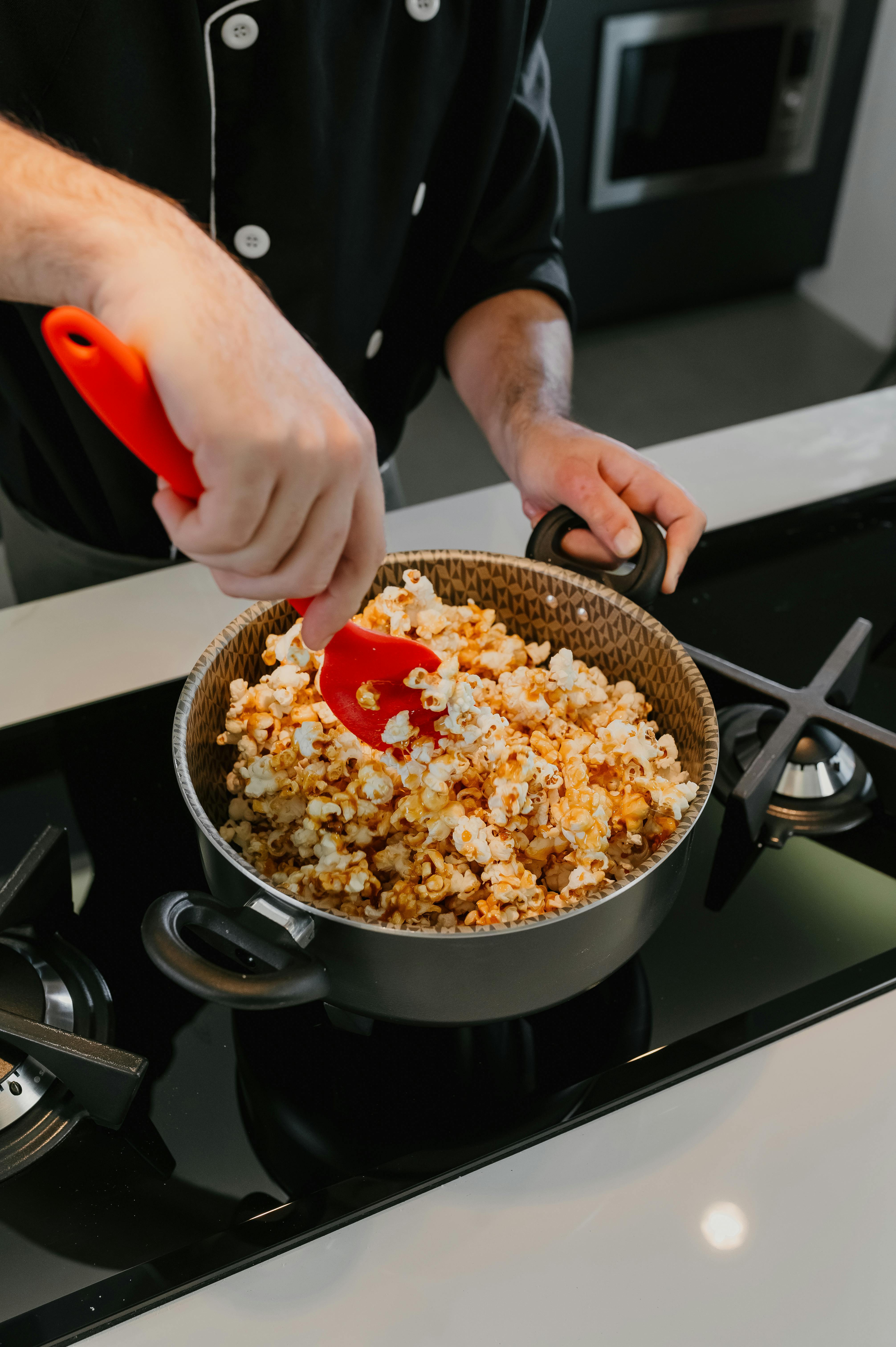 Chef stirring popcorn on modern stovetop · Free Stock Photo