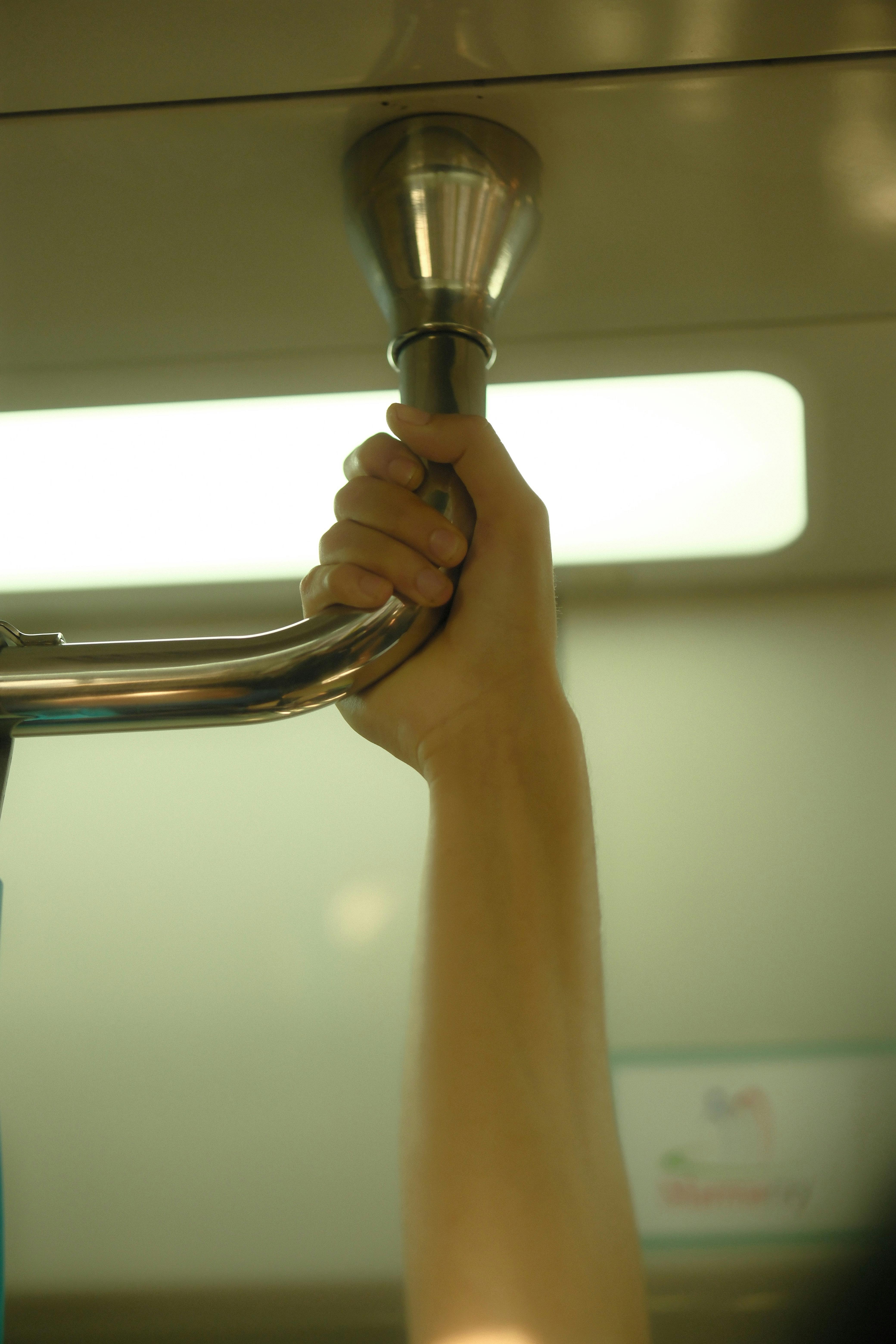 Close-up of hand gripping subway handrail · Free Stock Photo