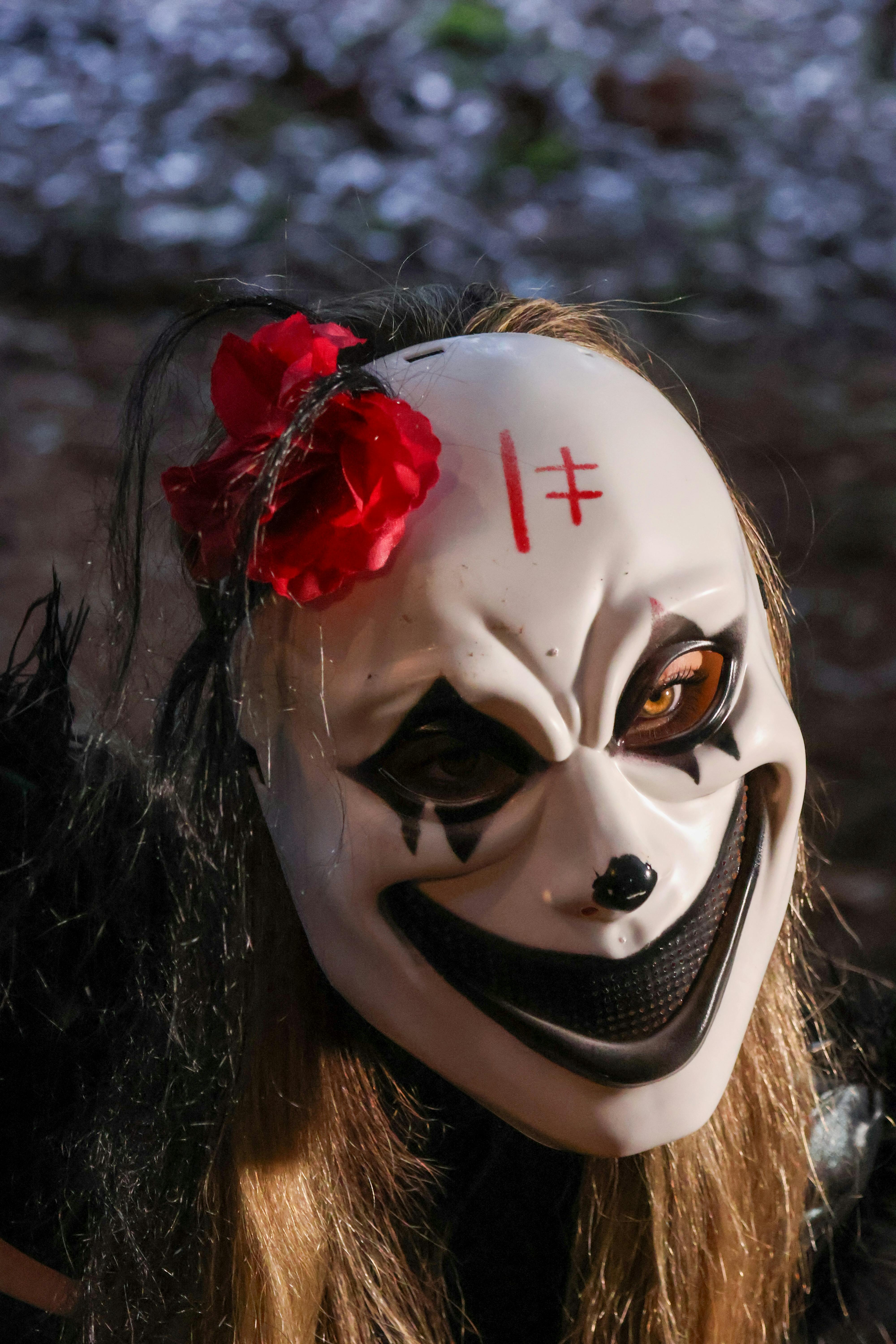 Creepy Clown Mask with Red Rose in Forest Setting · Free Stock Photo