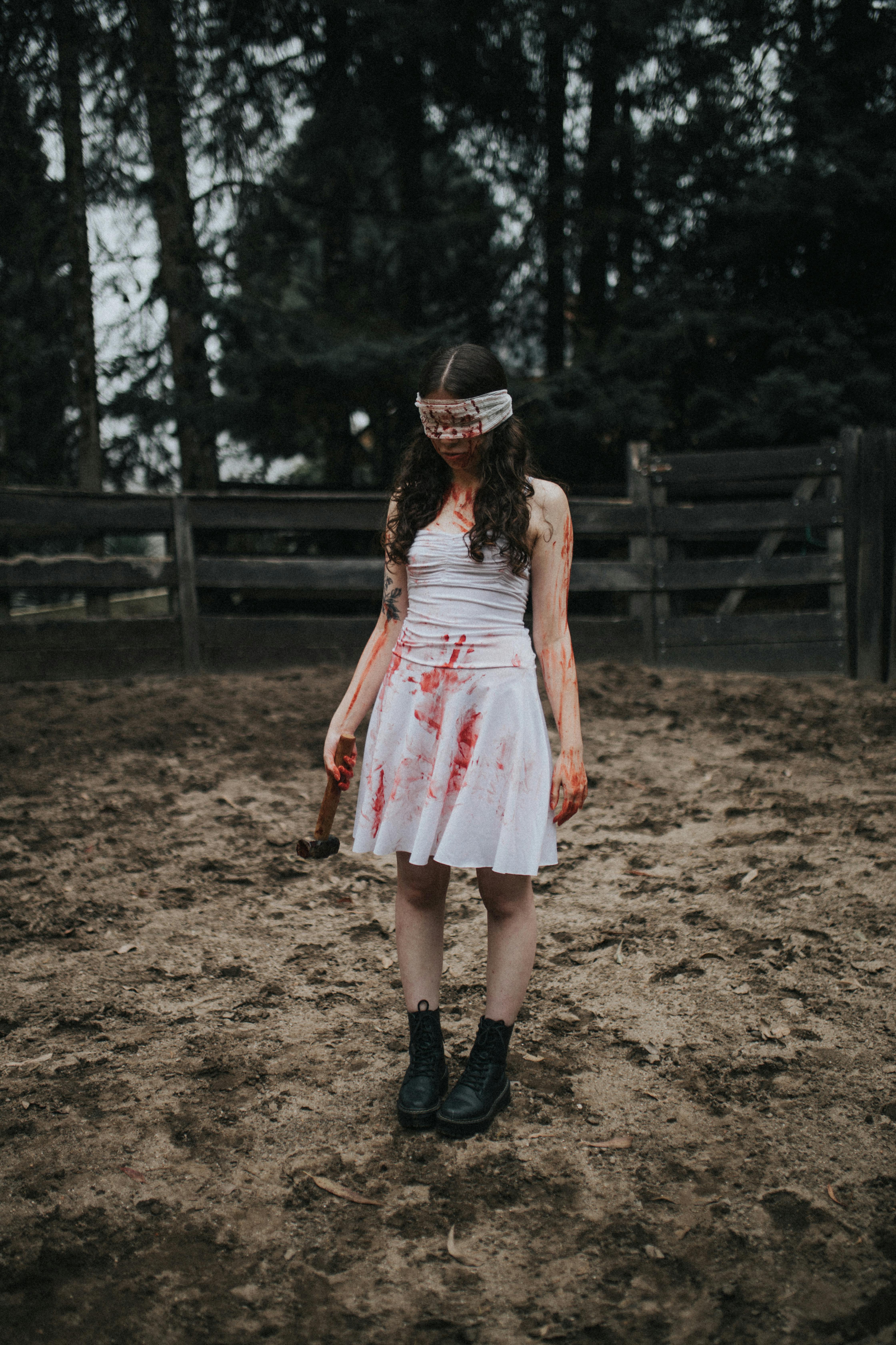Enigmatic Figure in Blood-Stained Dress Outdoors · Free Stock Photo